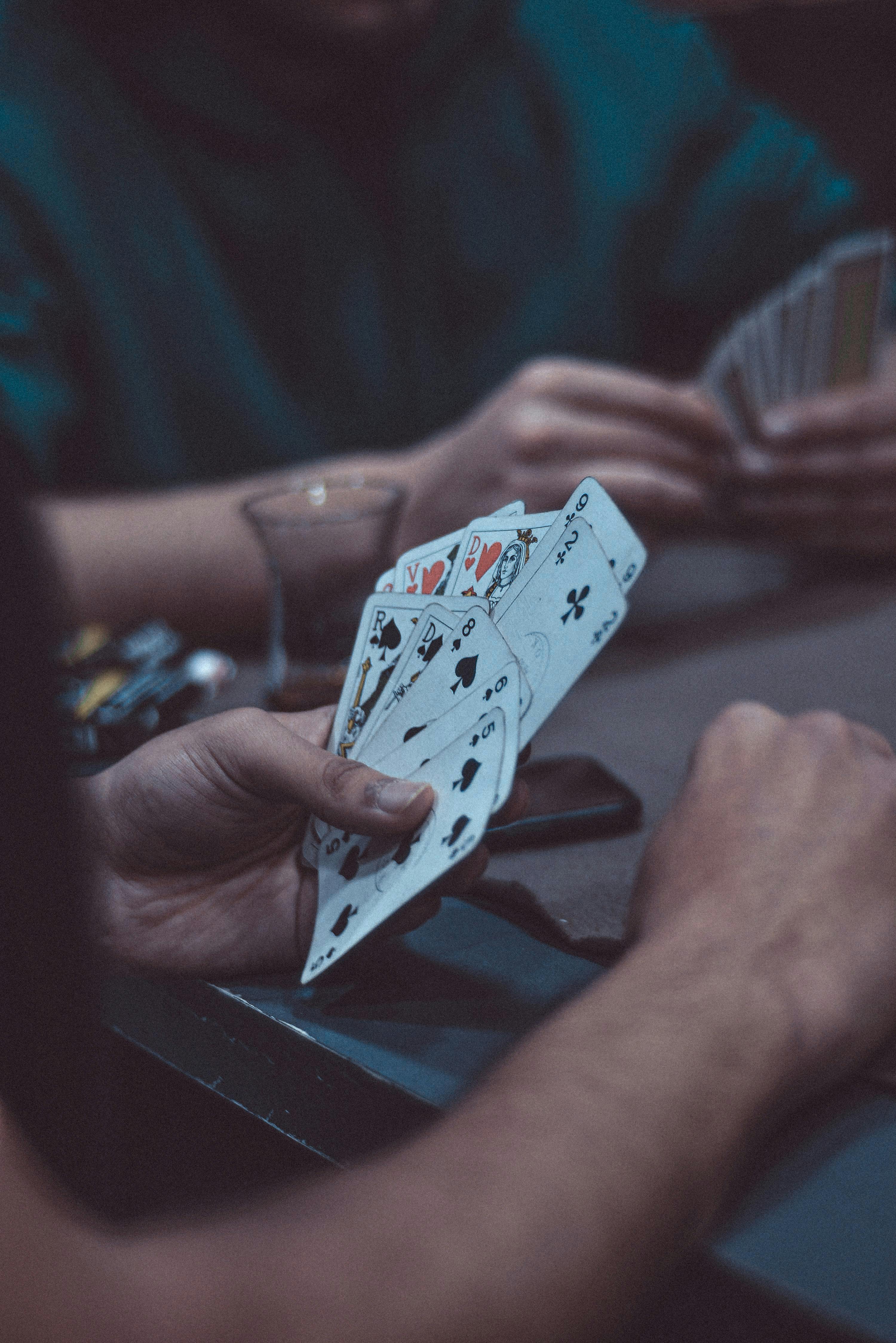 A person playing cards at a table with other people · Free Stock Photo
