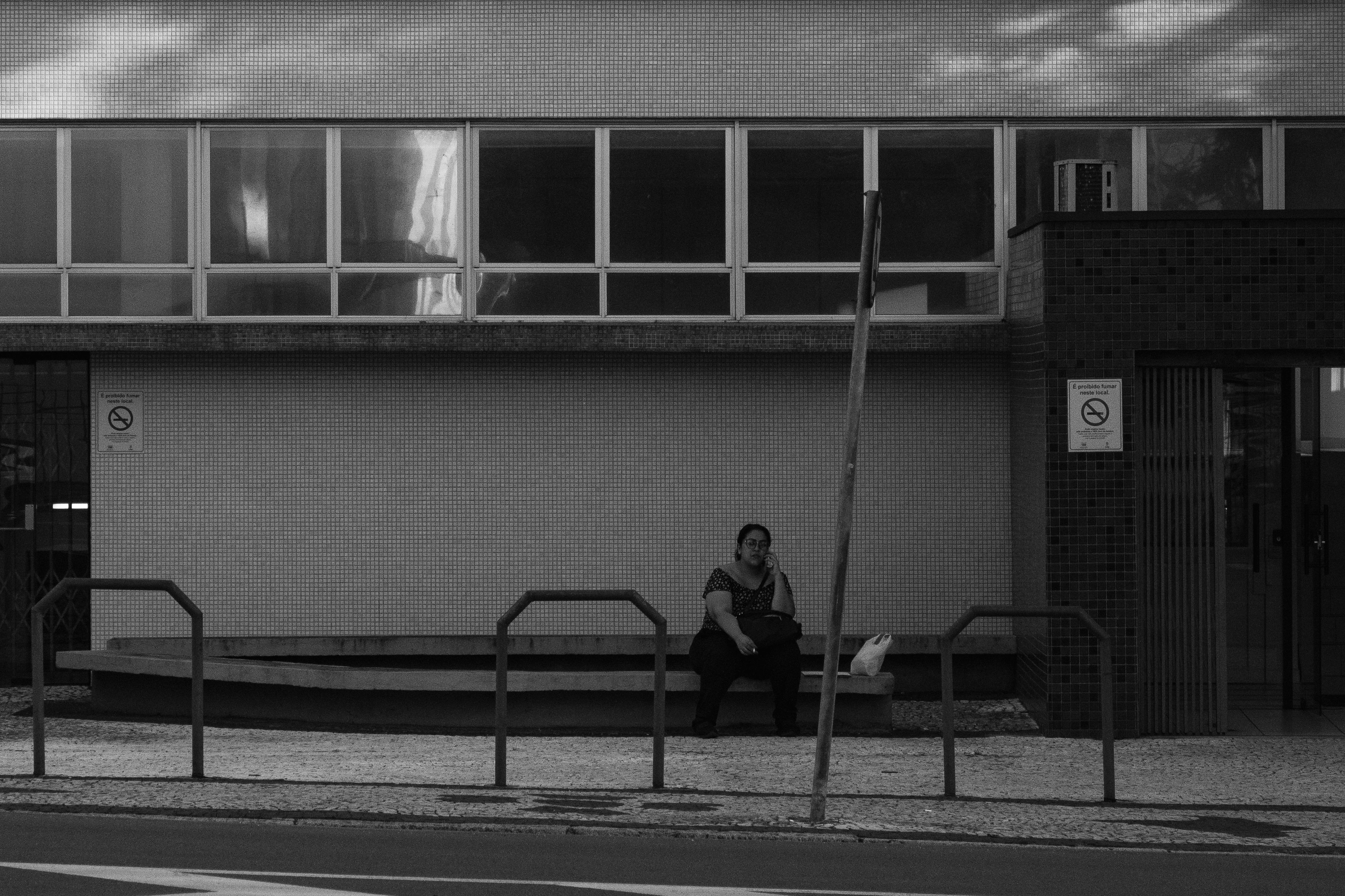 A person sitting on a bench outside of a building · Free Stock Photo