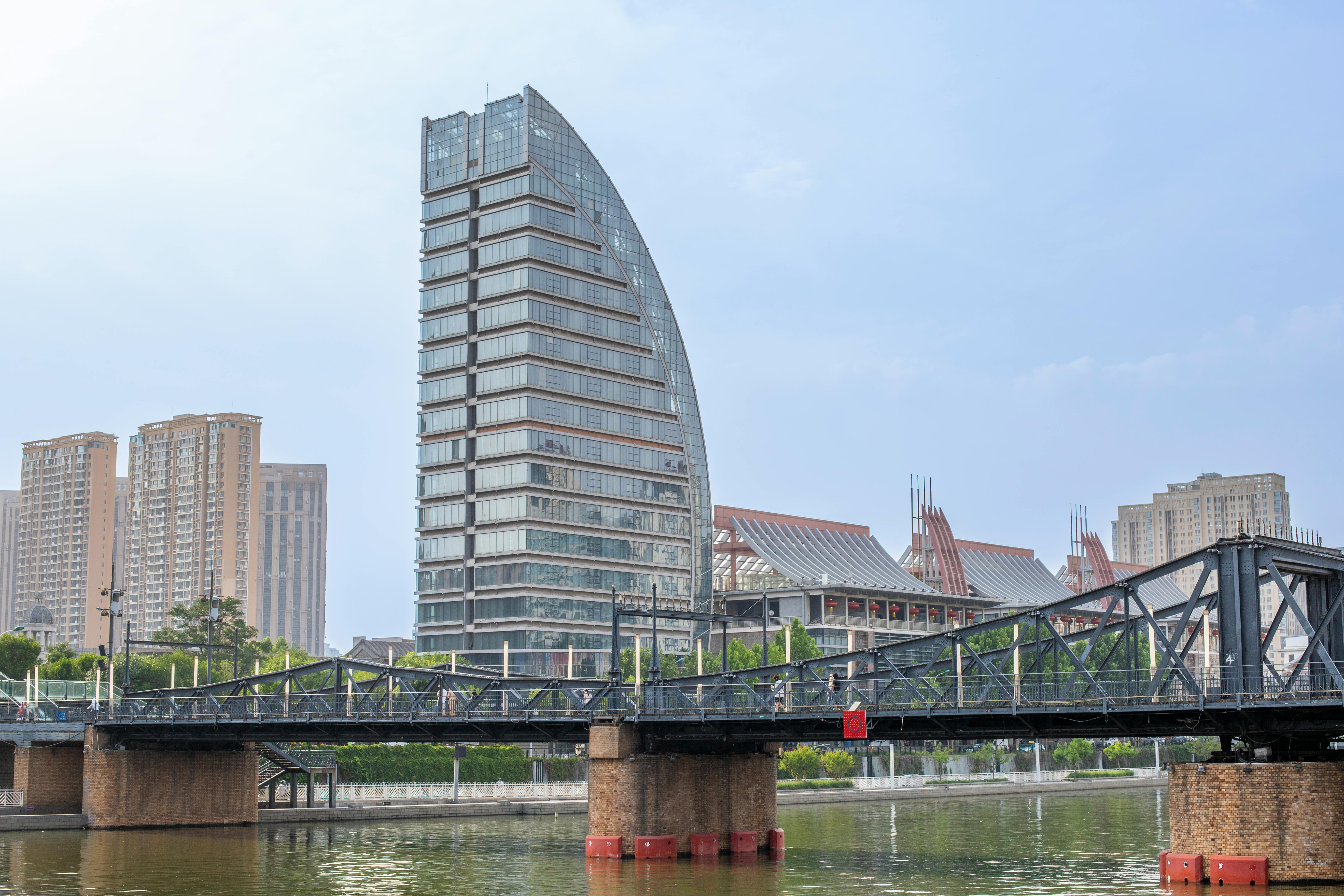 Bridge over a City River with a Modern Skyscraper in the Background ...