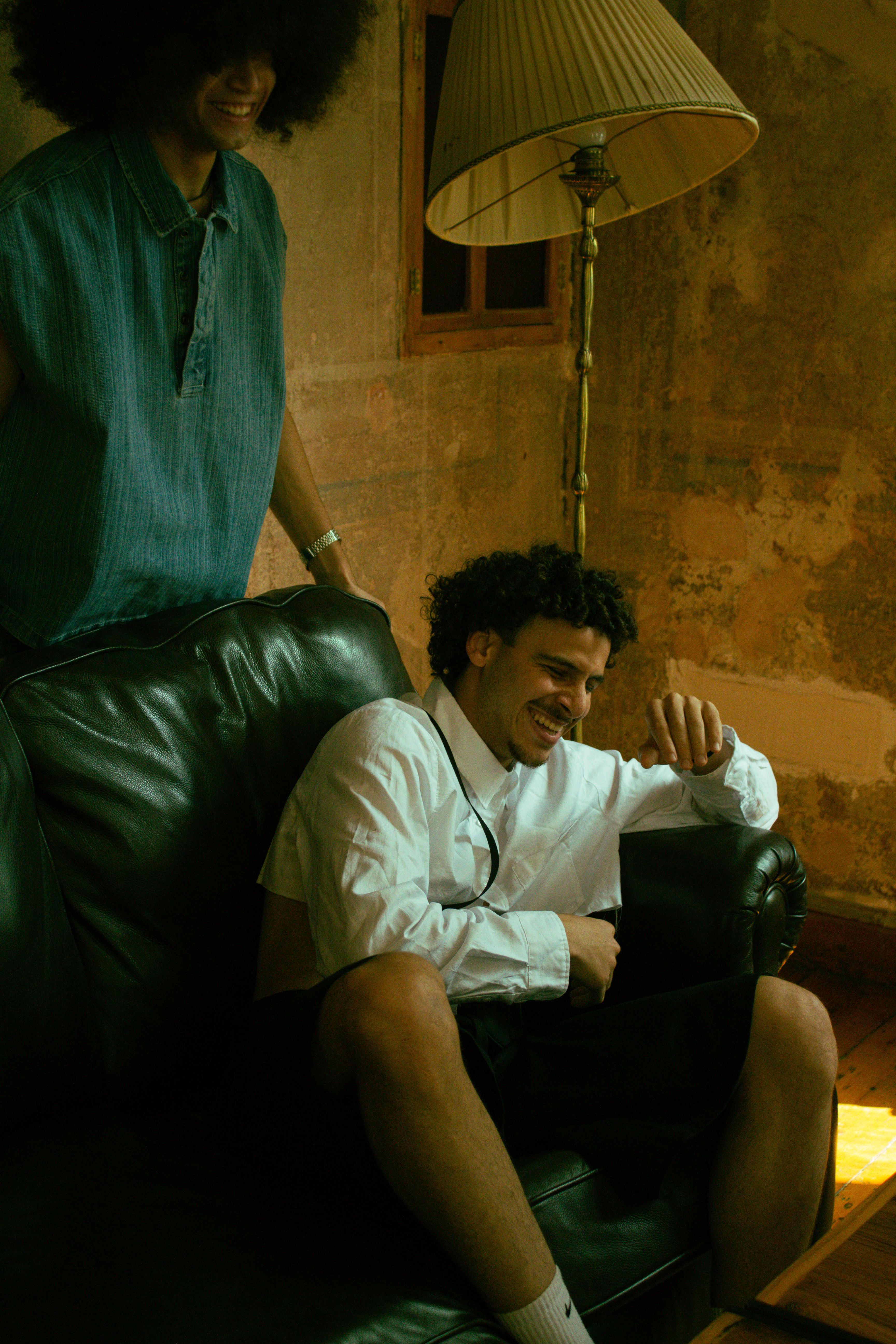 Men Sitting on and Standing behind Armchair · Free Stock Photo
