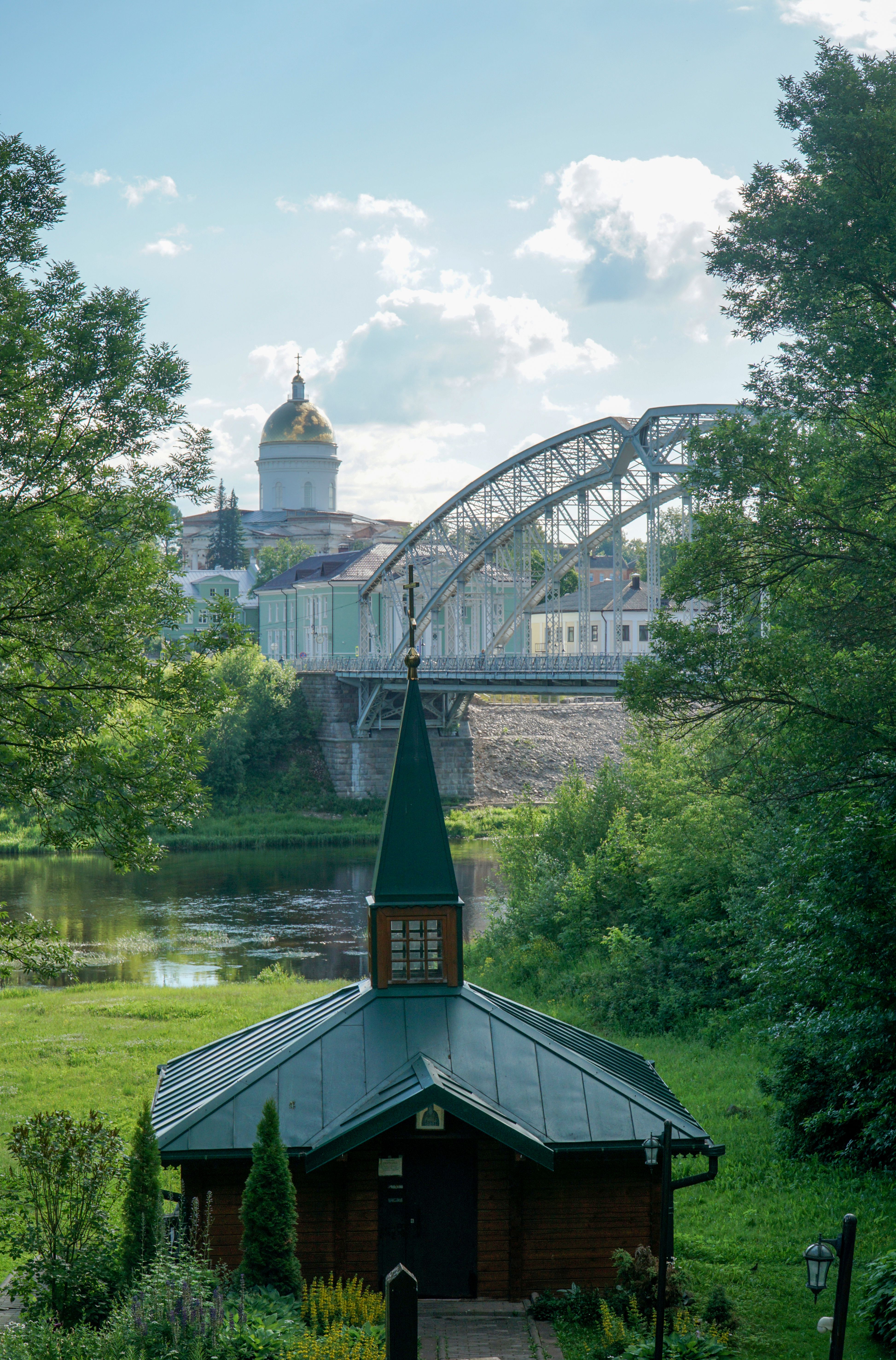 Small Chapel by River with Steel Arch Bridge · Free Stock Photo