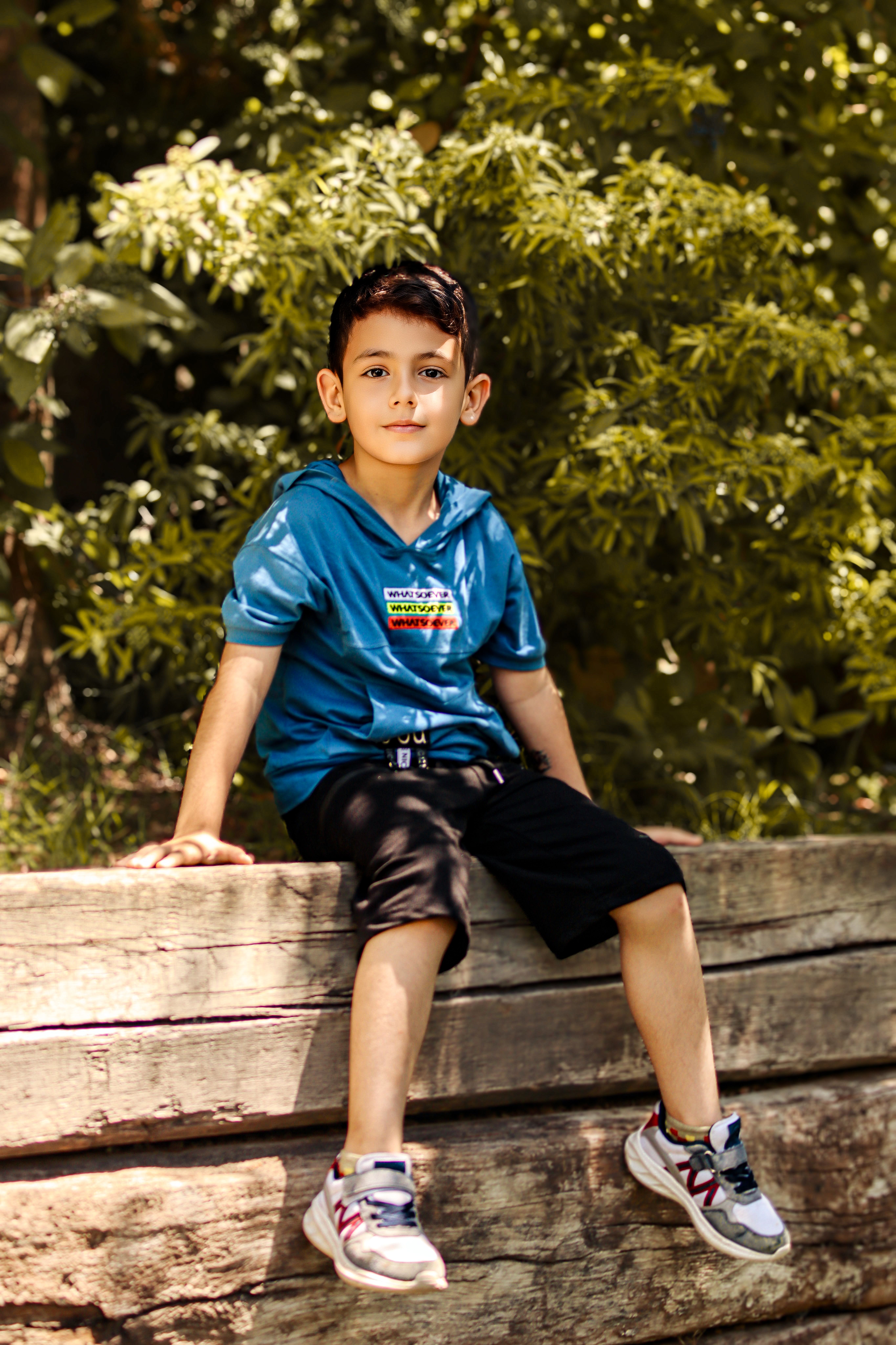 Boy Sitting on Wall in a Park · Free Stock Photo
