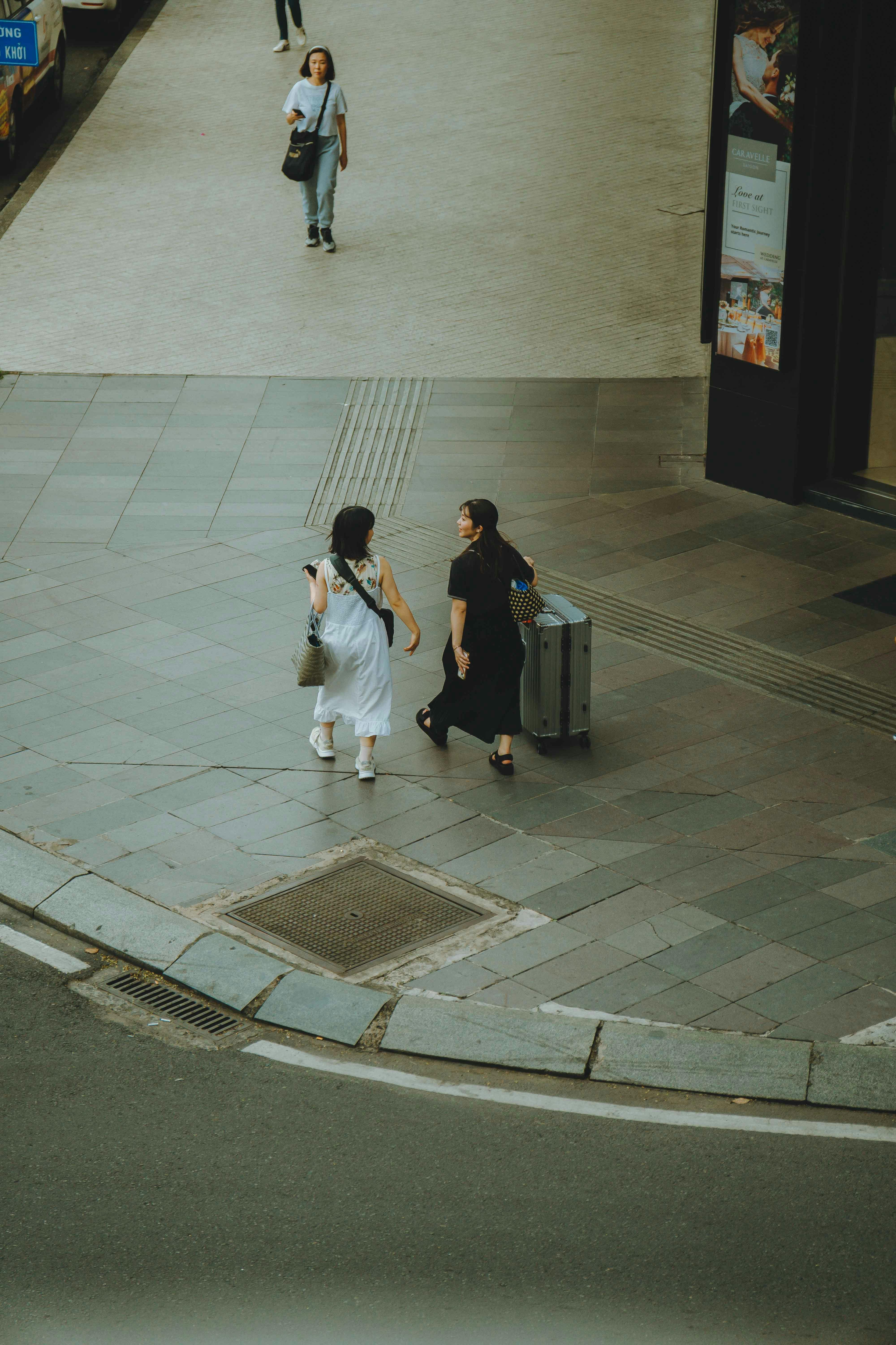 Two people walking down a street with luggage · Free Stock Photo