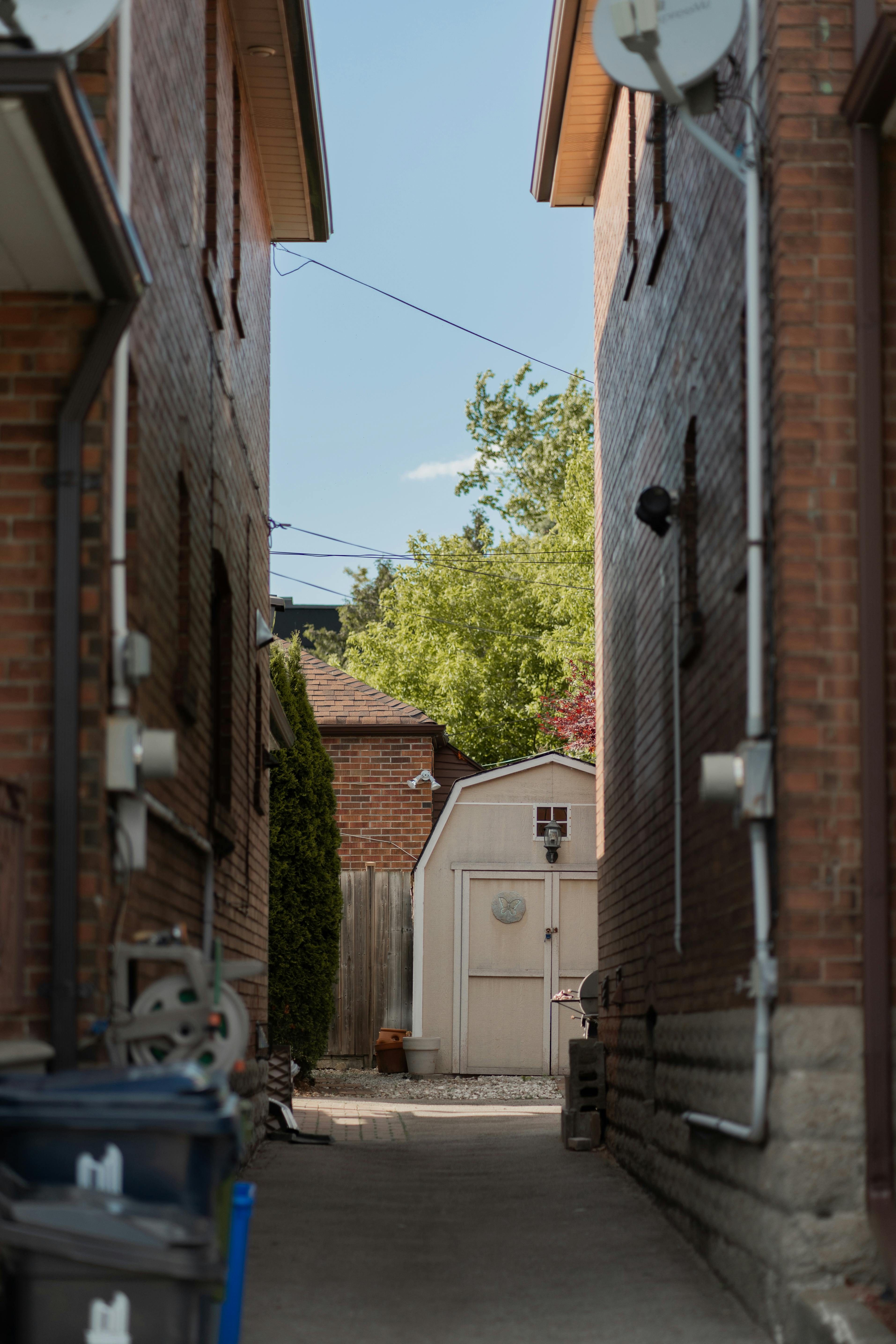 Narrow Alley Between Two Brick Houses Leading to a Shed · Free Stock Photo
