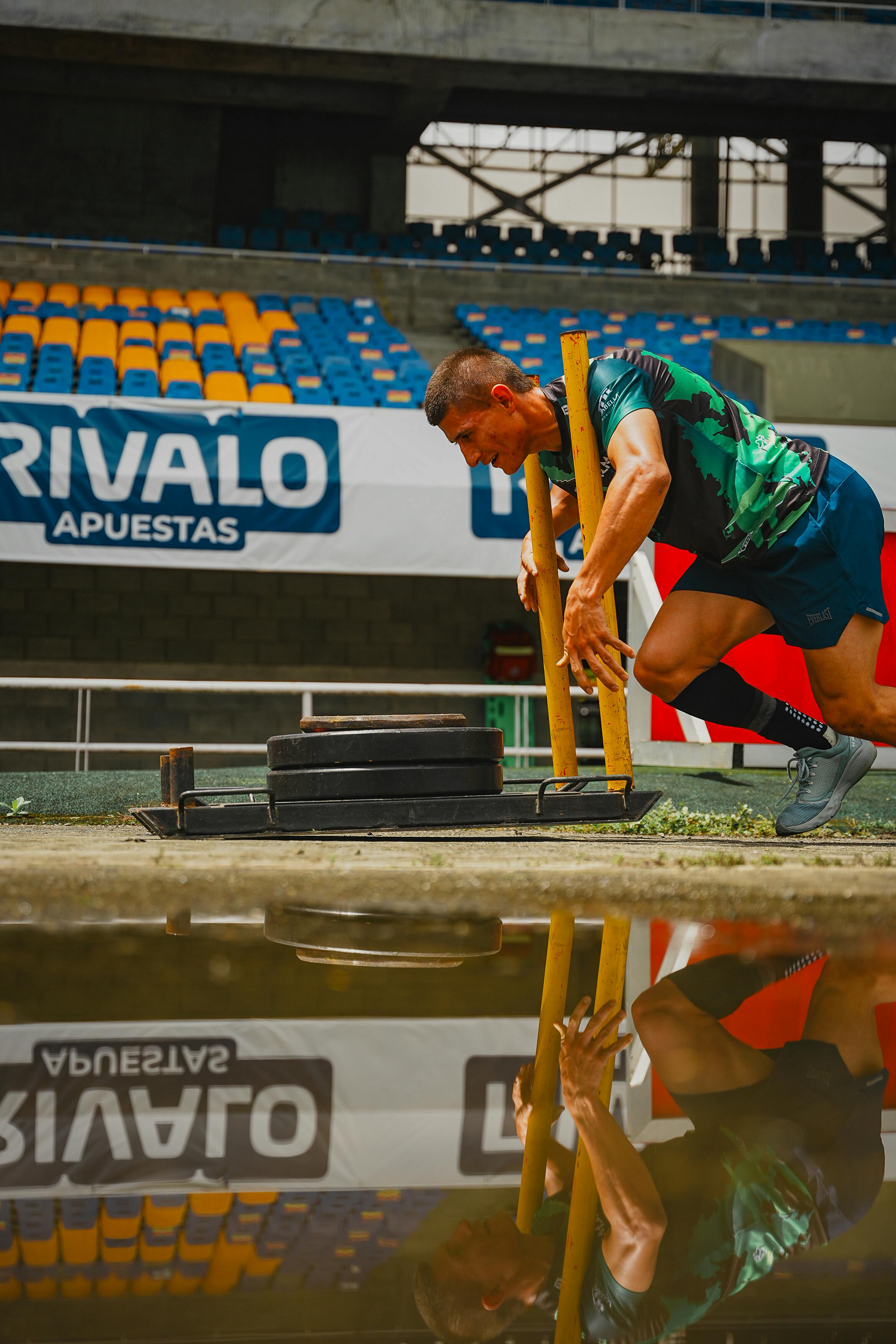 Man Athlete Pushing Sled on Wet Stadium · Free Stock Photo