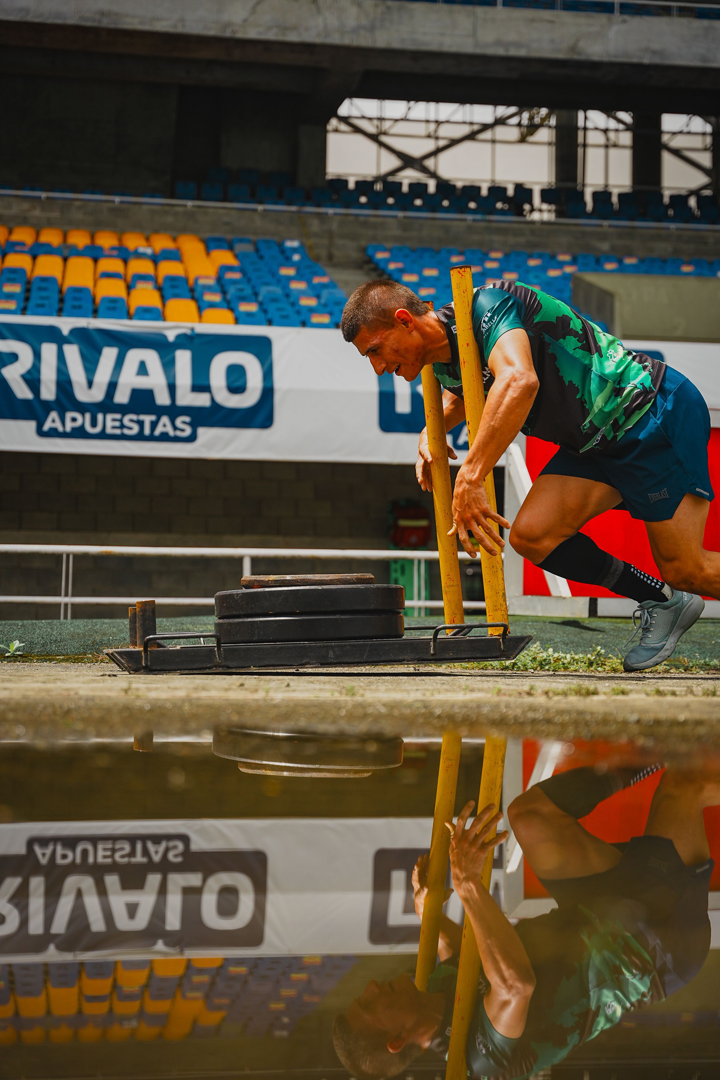 Man Athlete Pushing Sled on Wet Stadium · Free Stock Photo