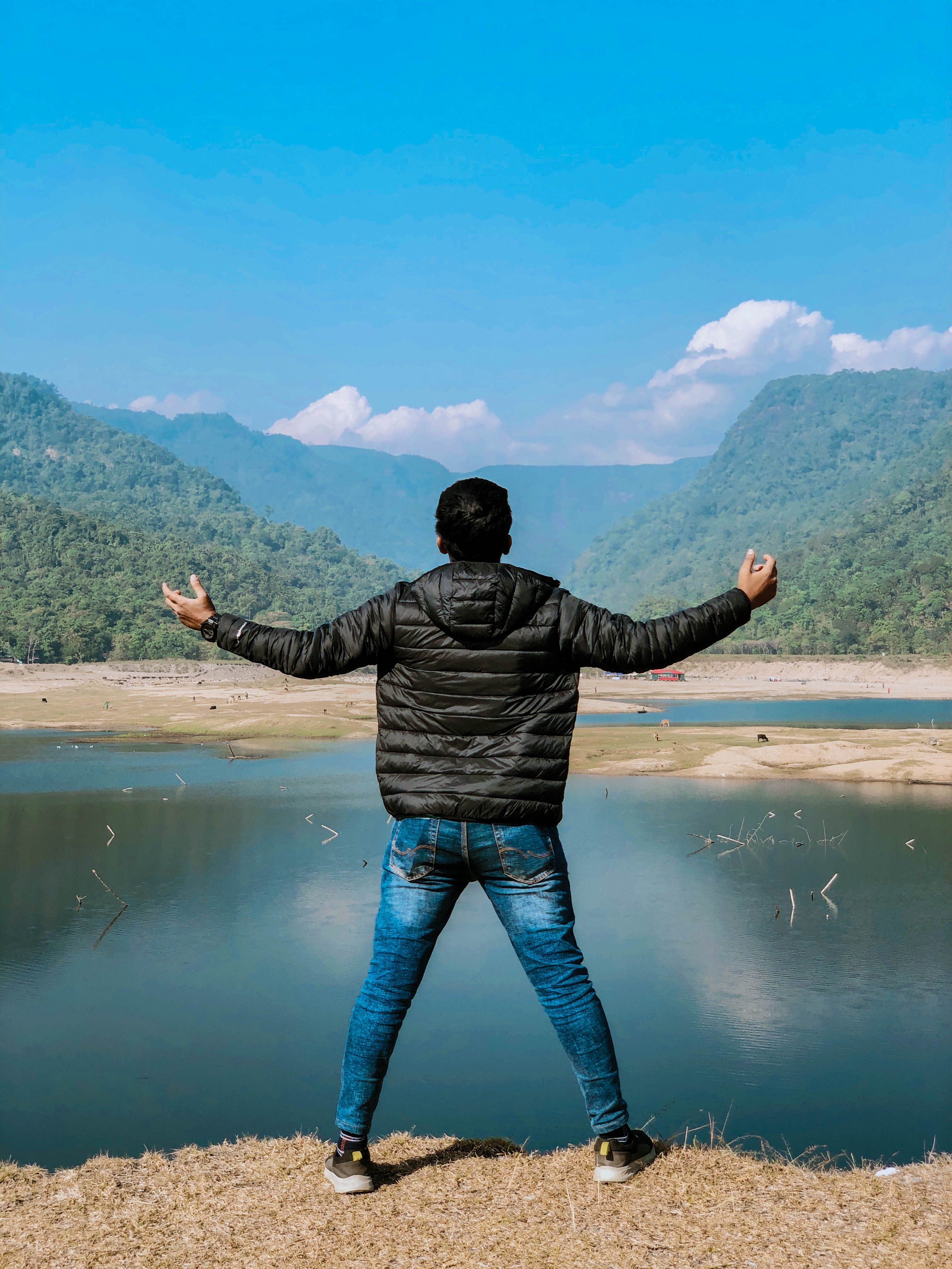 Back View of a Man Standing on a Lakeshore in the Mountains · Free ...