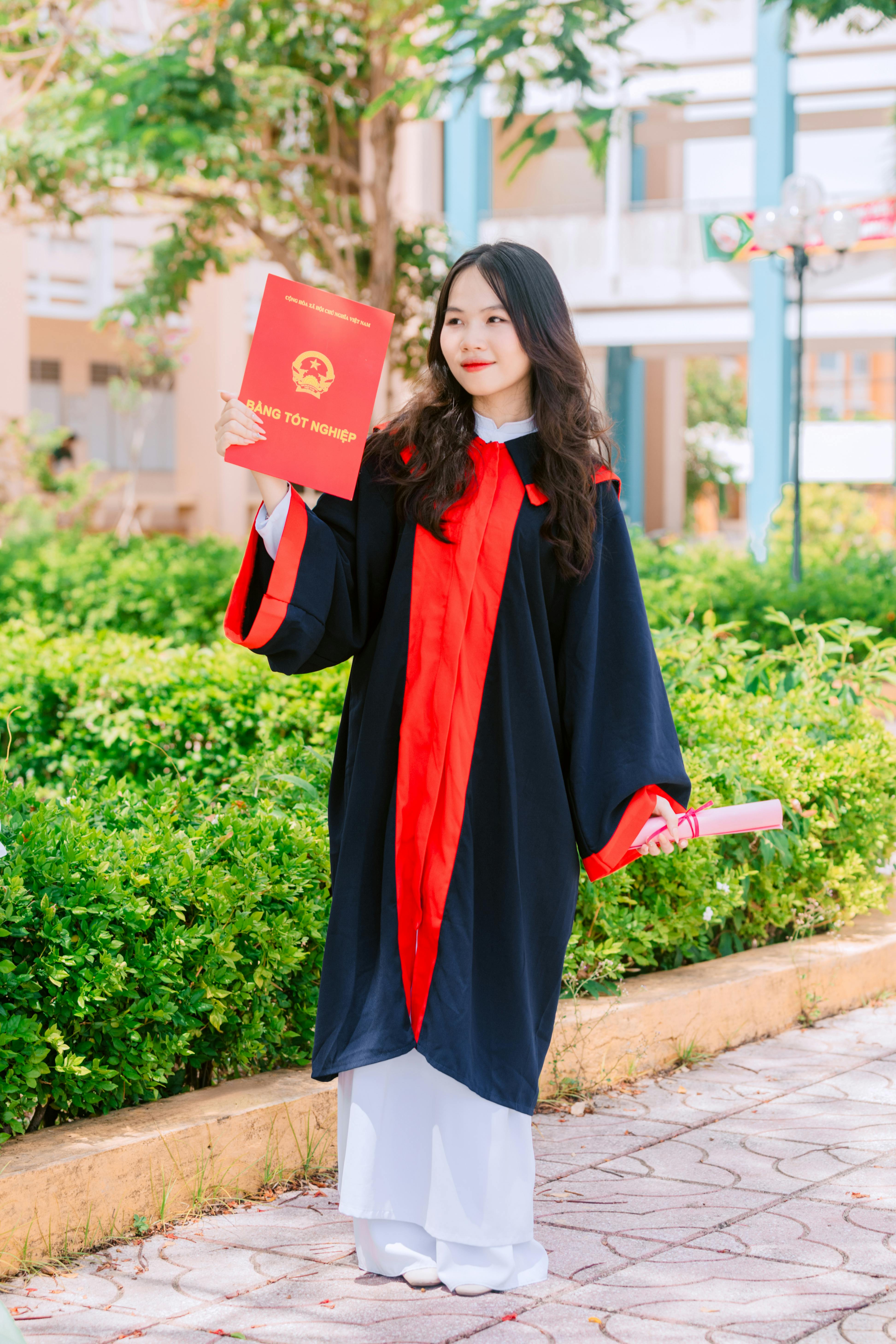 A Woman Wearing a Graduation Gown Holding the Diploma · Free Stock Photo