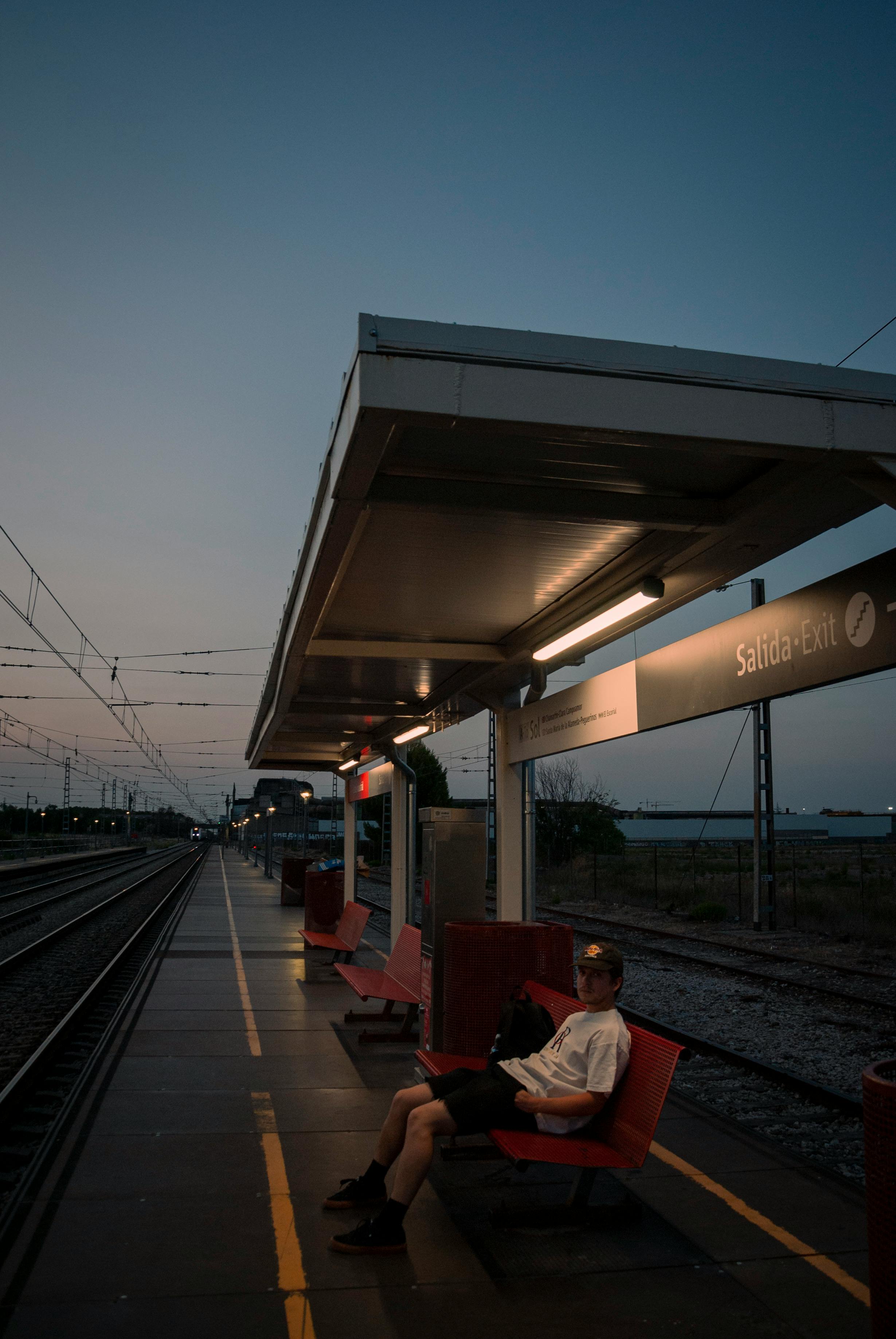Man Sitting at Railway Station at Dusk · Free Stock Photo