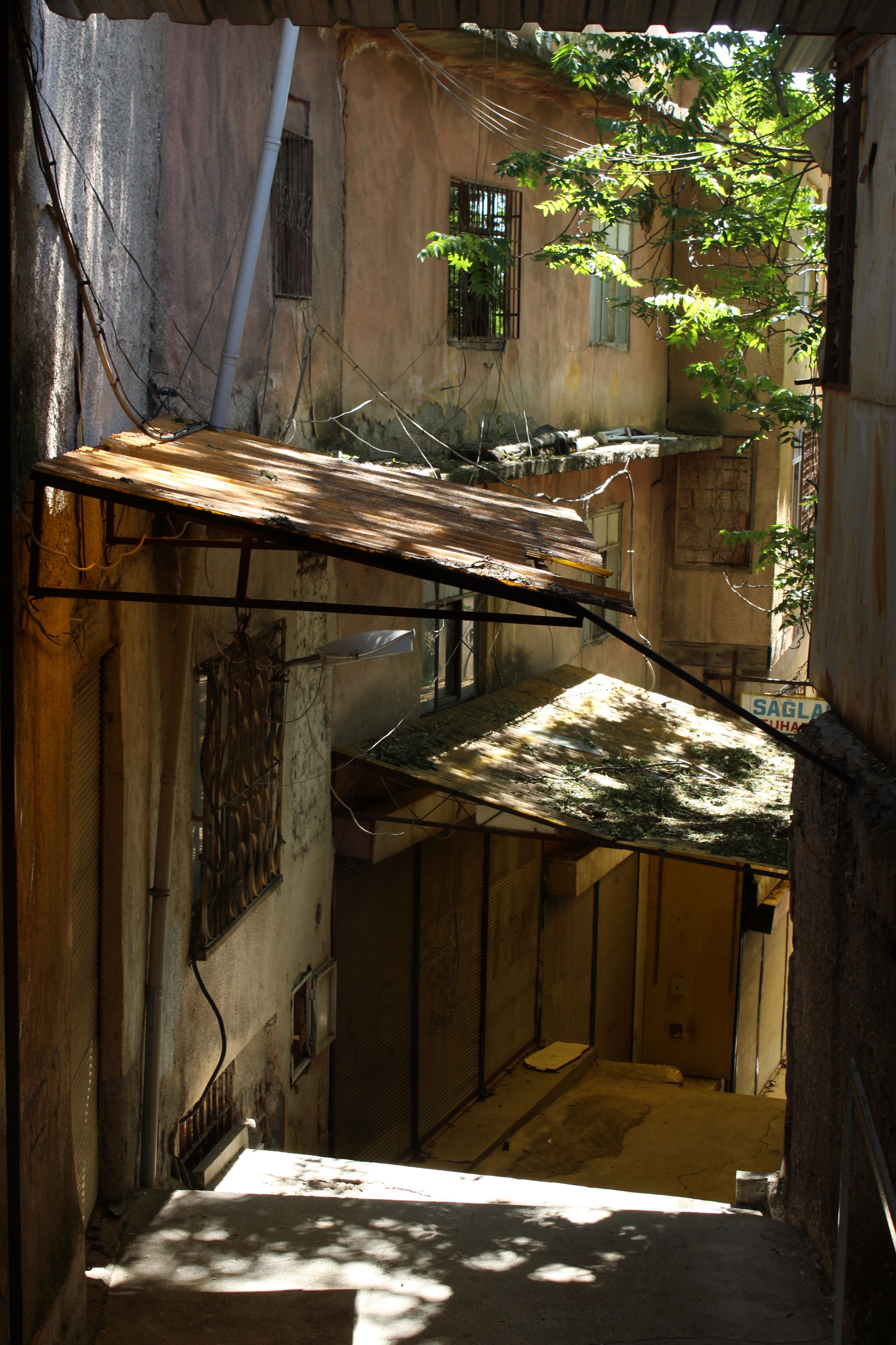 A narrow alleyway with a tree and a roof · Free Stock Photo