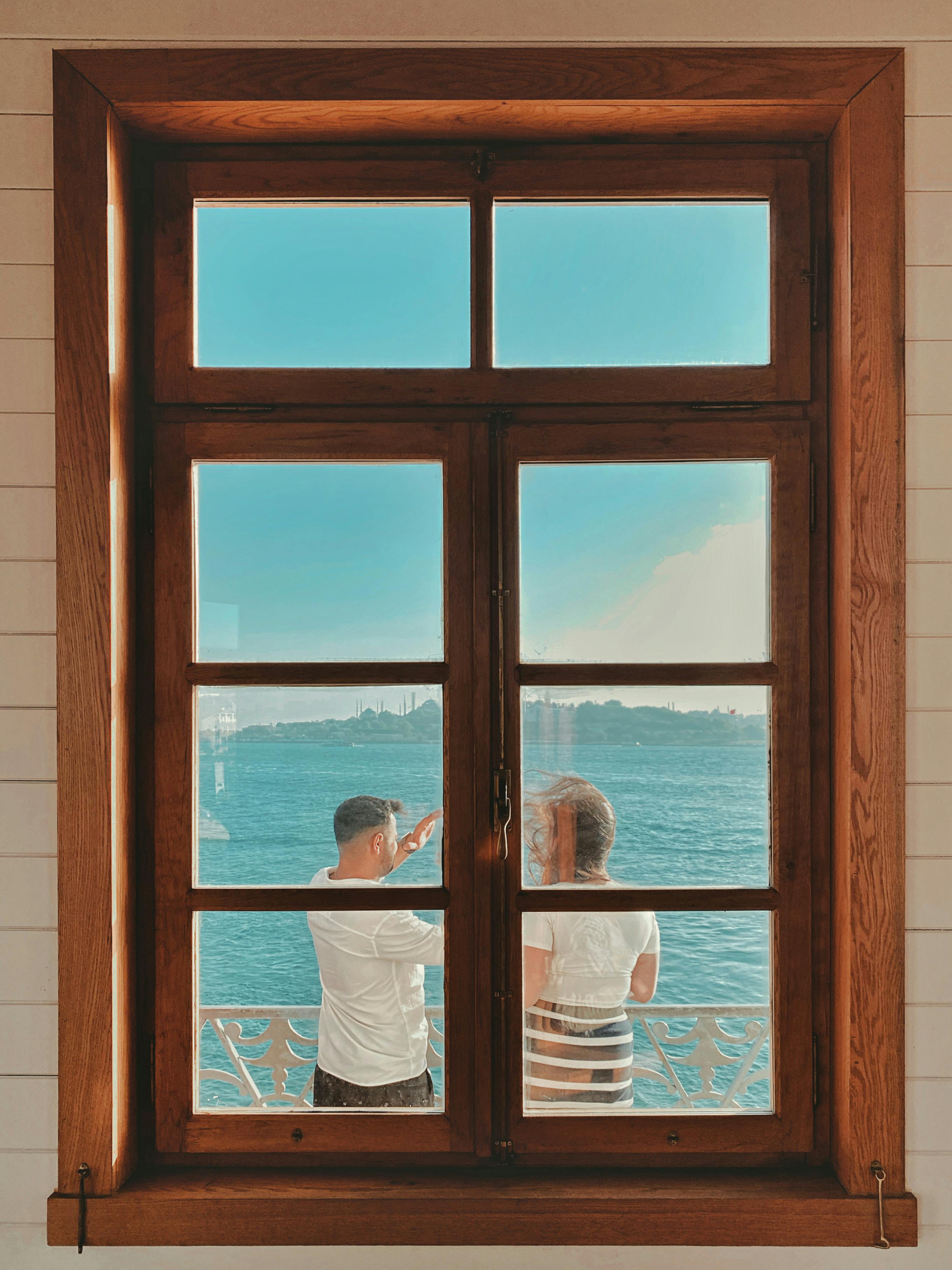 Man and a Woman Standing on a Balcony Seen through a Paned Window ...