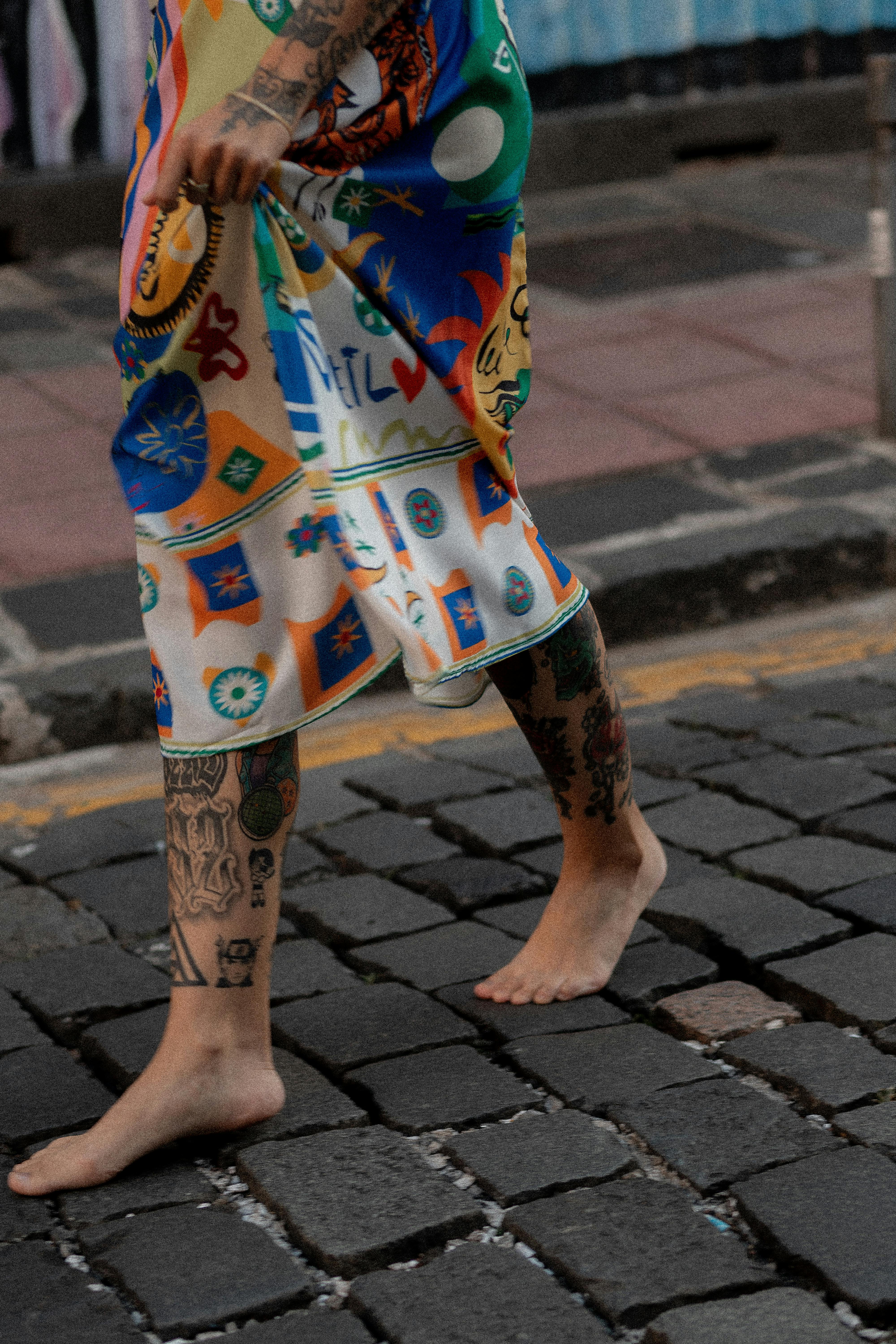 A woman with tattoos walking down a street · Free Stock Photo