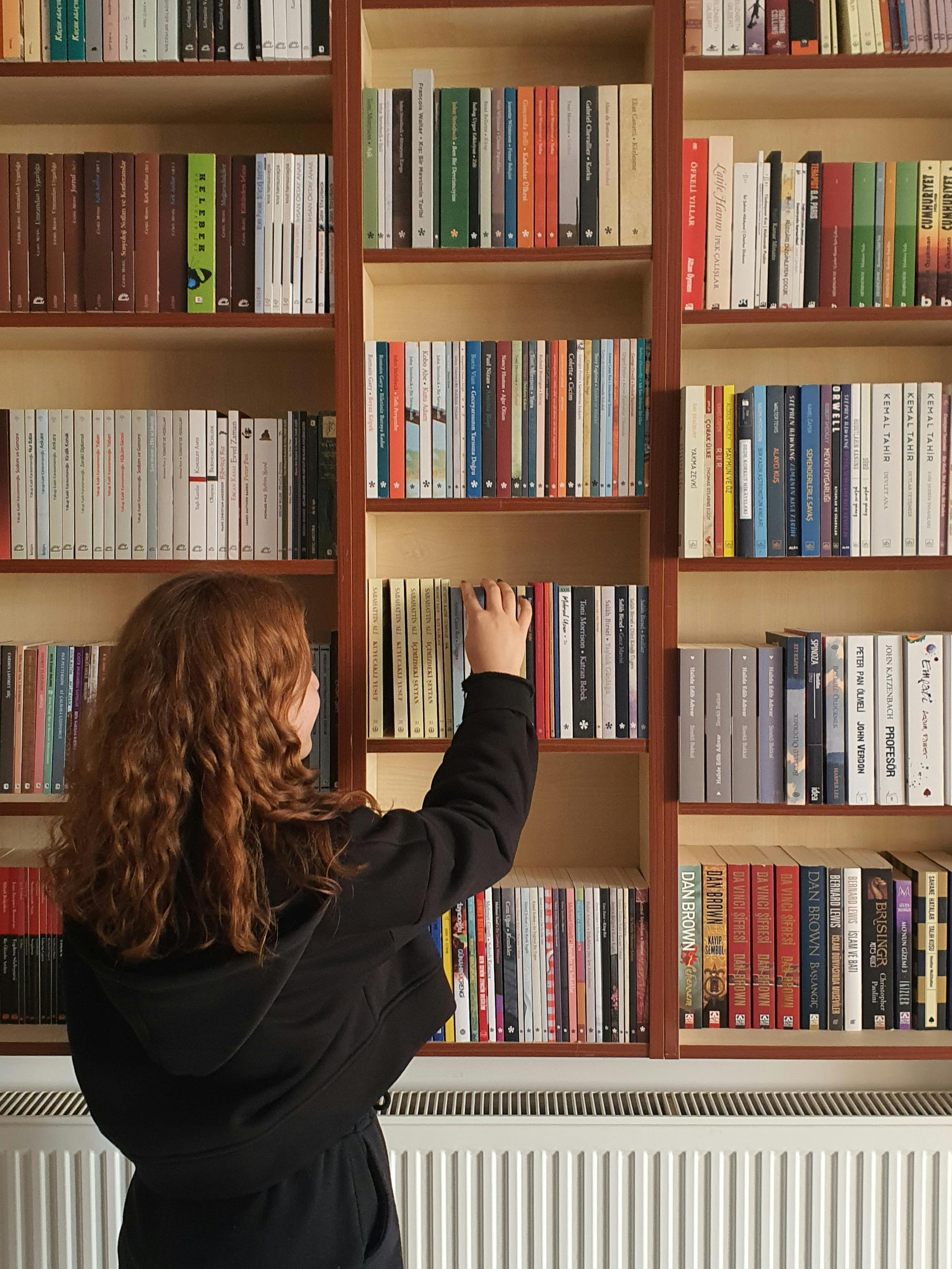 A Woman Picking a Book from the Shelf · Free Stock Photo