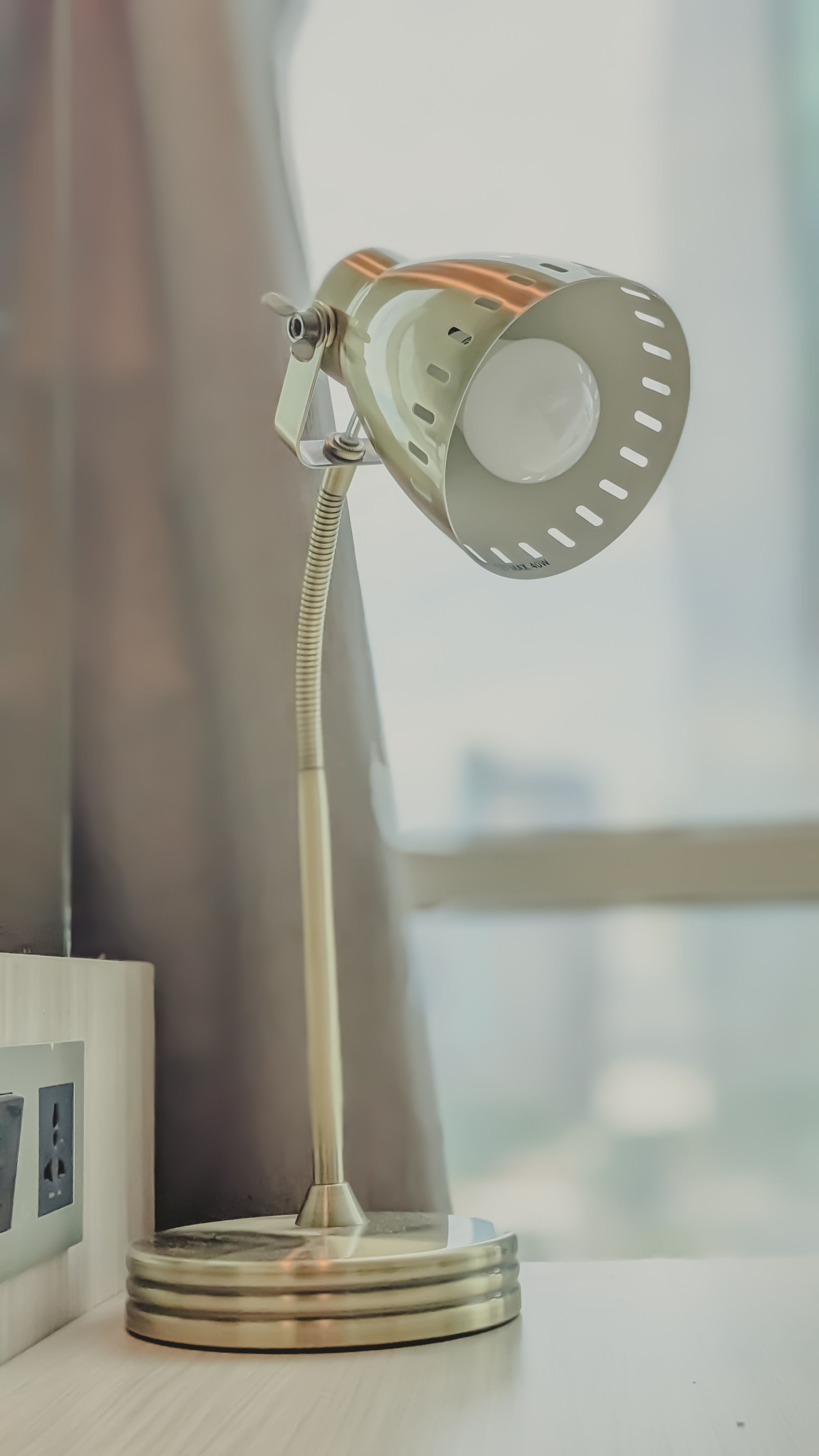 Front view of a golden-coated antique desk lamp placed on the table ...