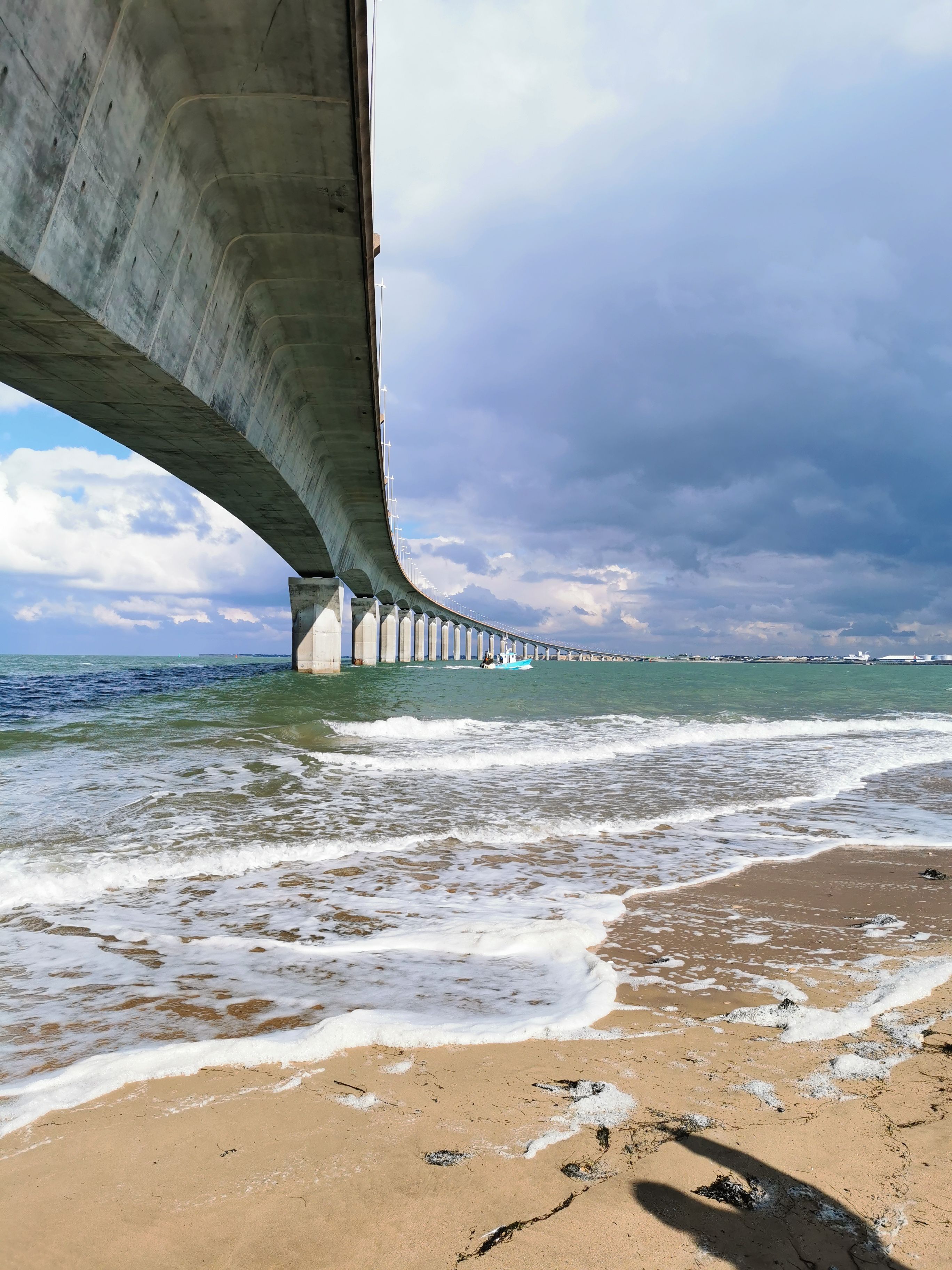 A bridge over the ocean with waves crashing on the shore · Free Stock Photo