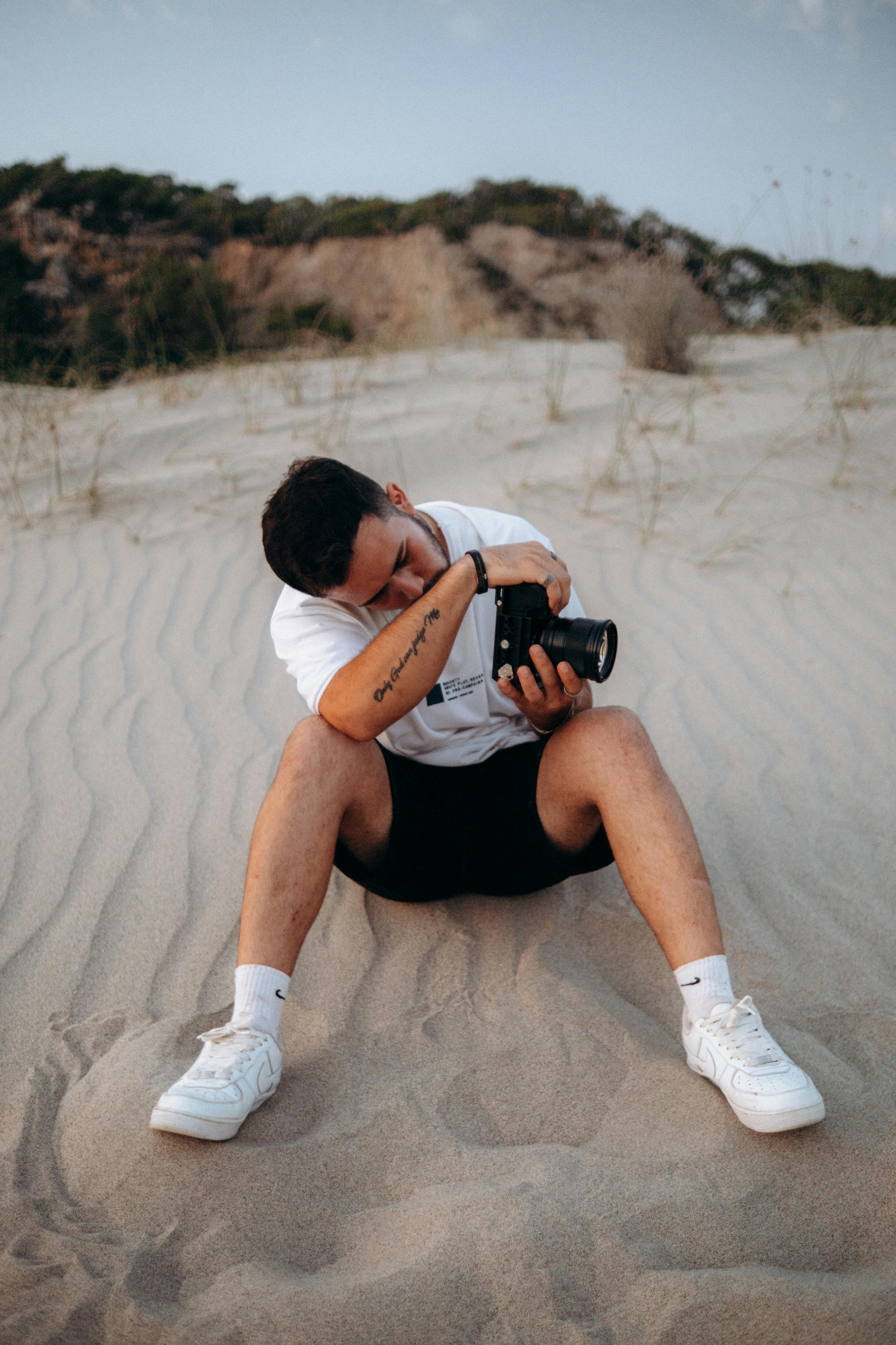 Man Sitting with Camera on Beach · Free Stock Photo