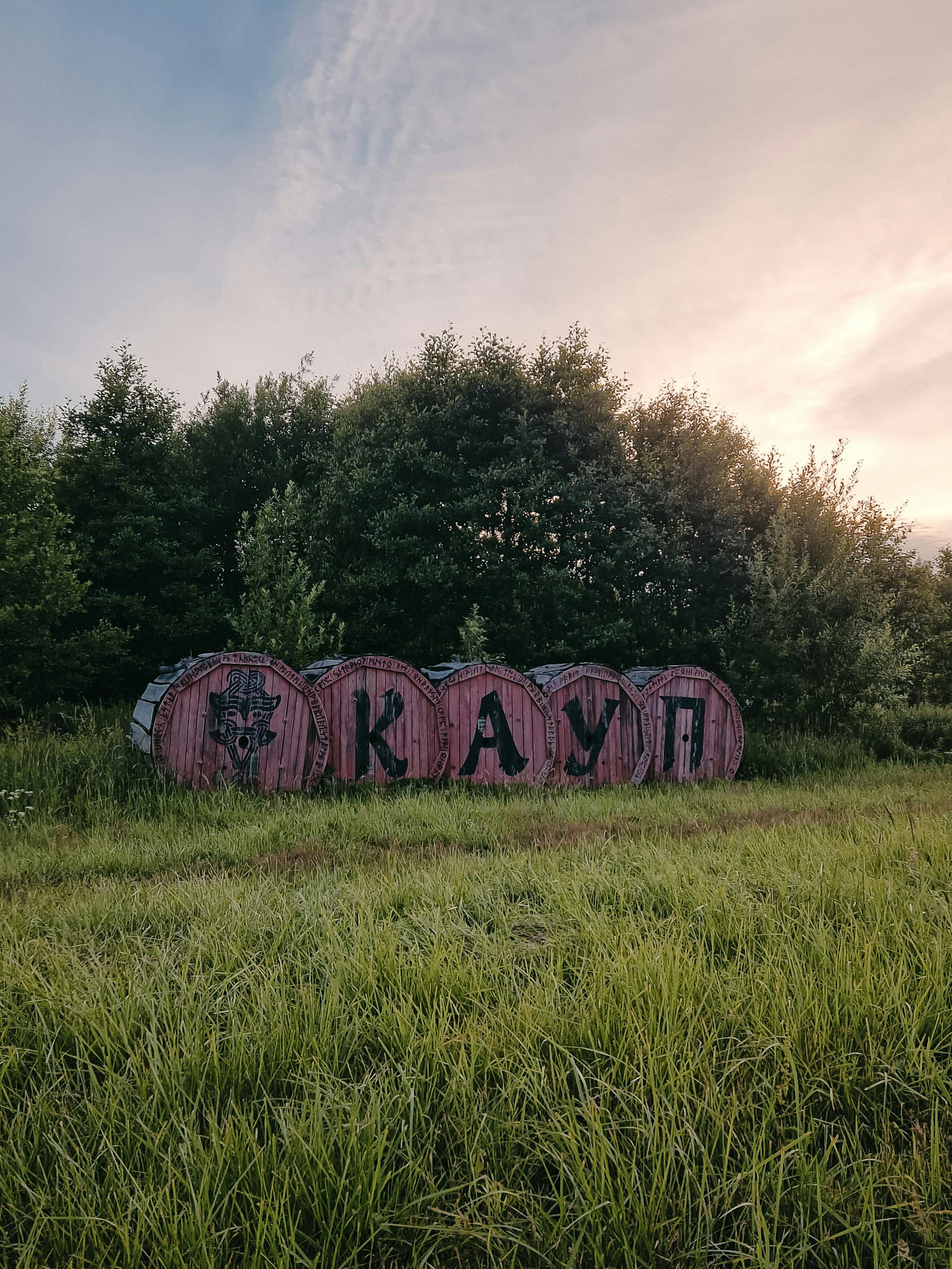 Letters on Wooden Sheds on Field · Free Stock Photo