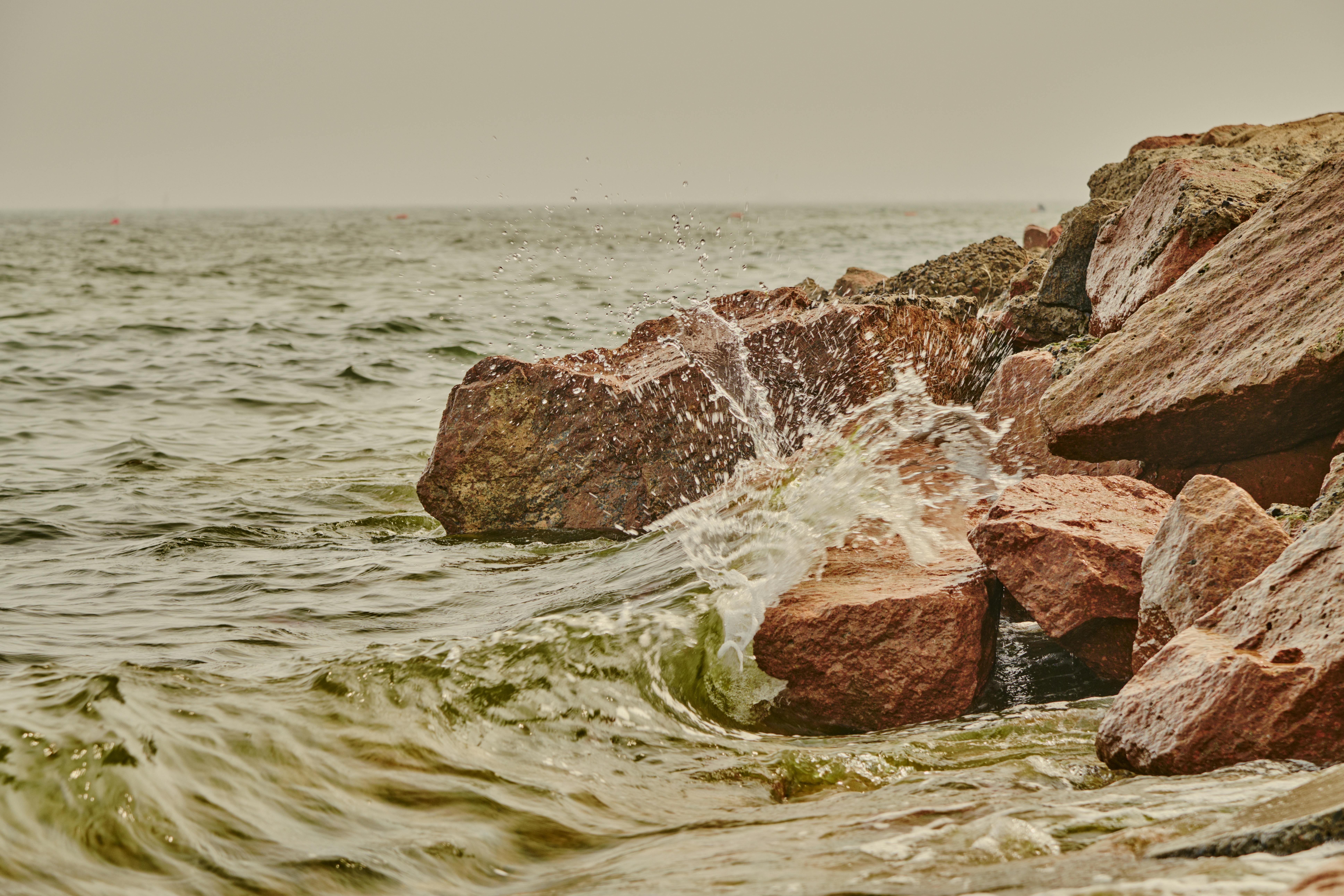 A rocky shoreline with waves crashing into the rocks · Free Stock Photo