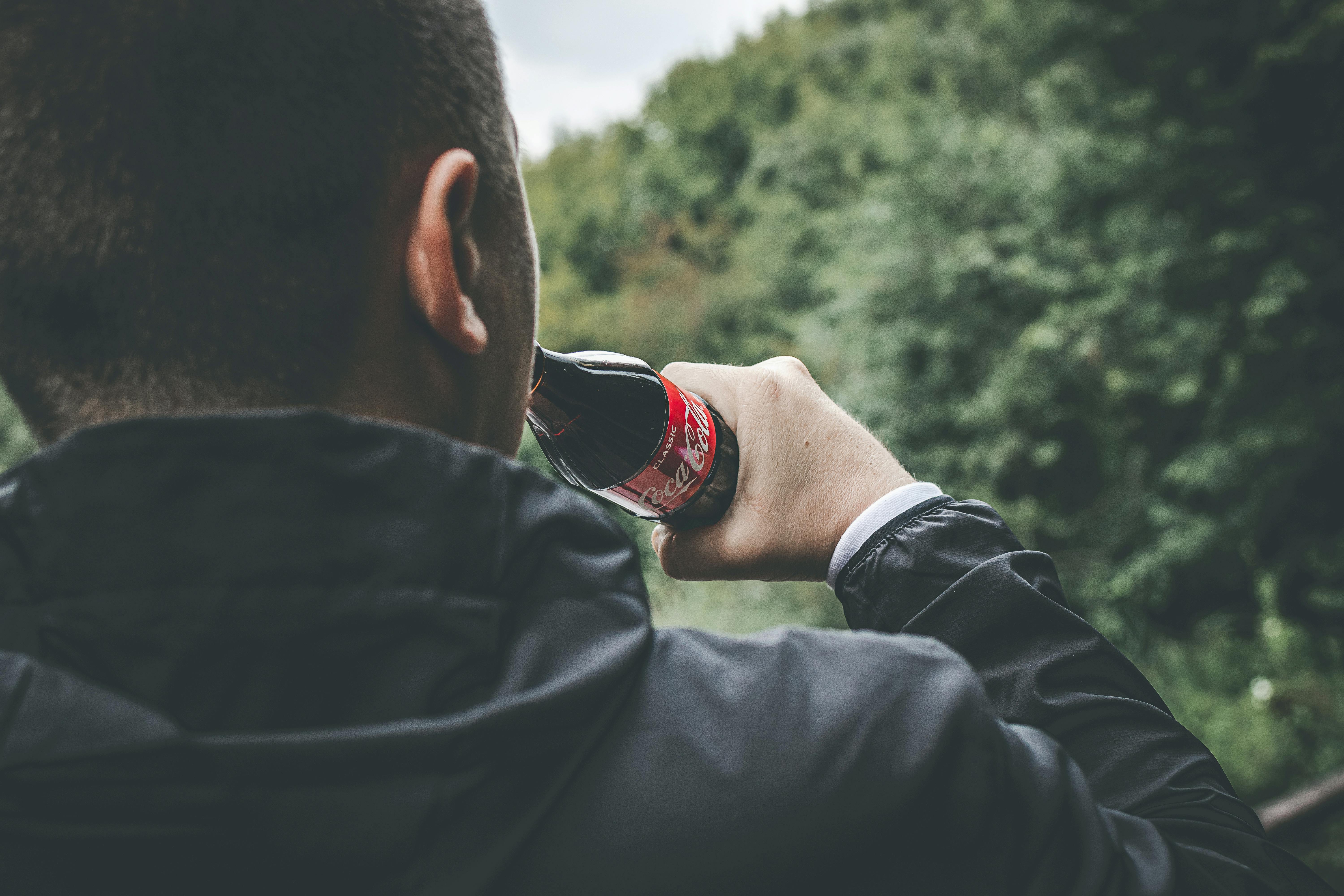 Two Men Drinking Coca-cola Near Coca-cola Stall · Free Stock Photo