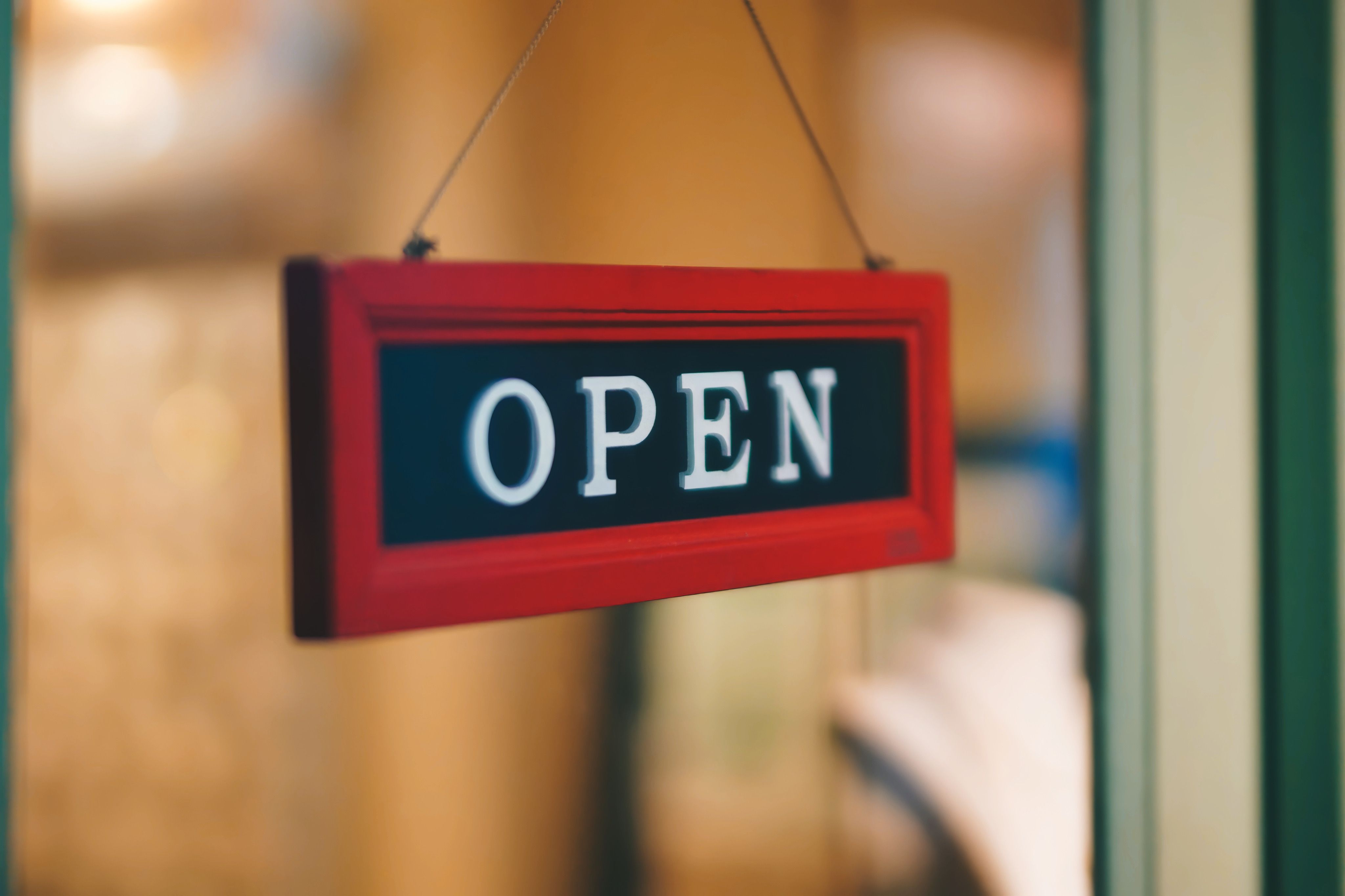 Happy woman showing wooden signboard saying open · Free Stock Photo