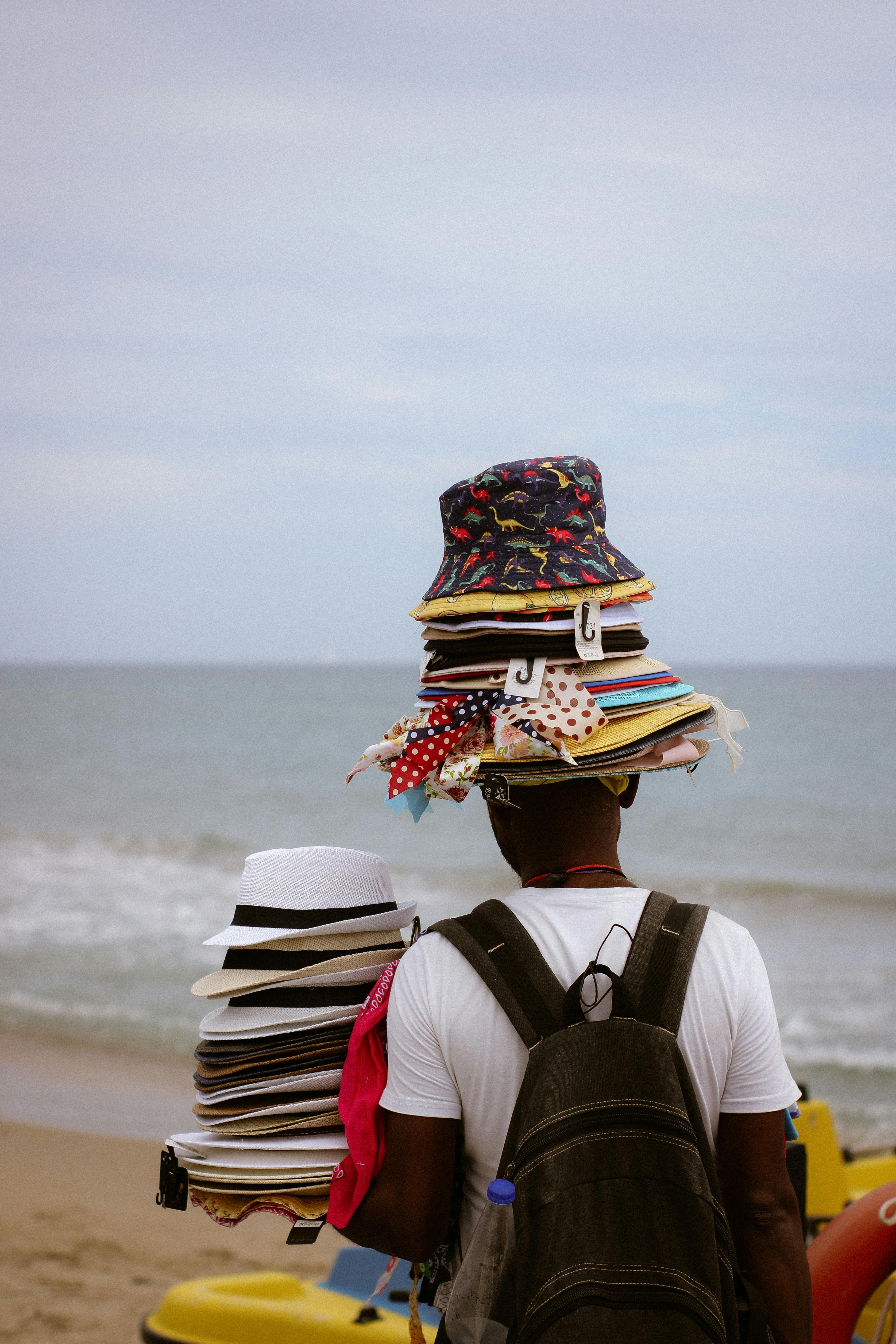 Back View of a Man Selling Hats on the Beach · Free Stock Photo