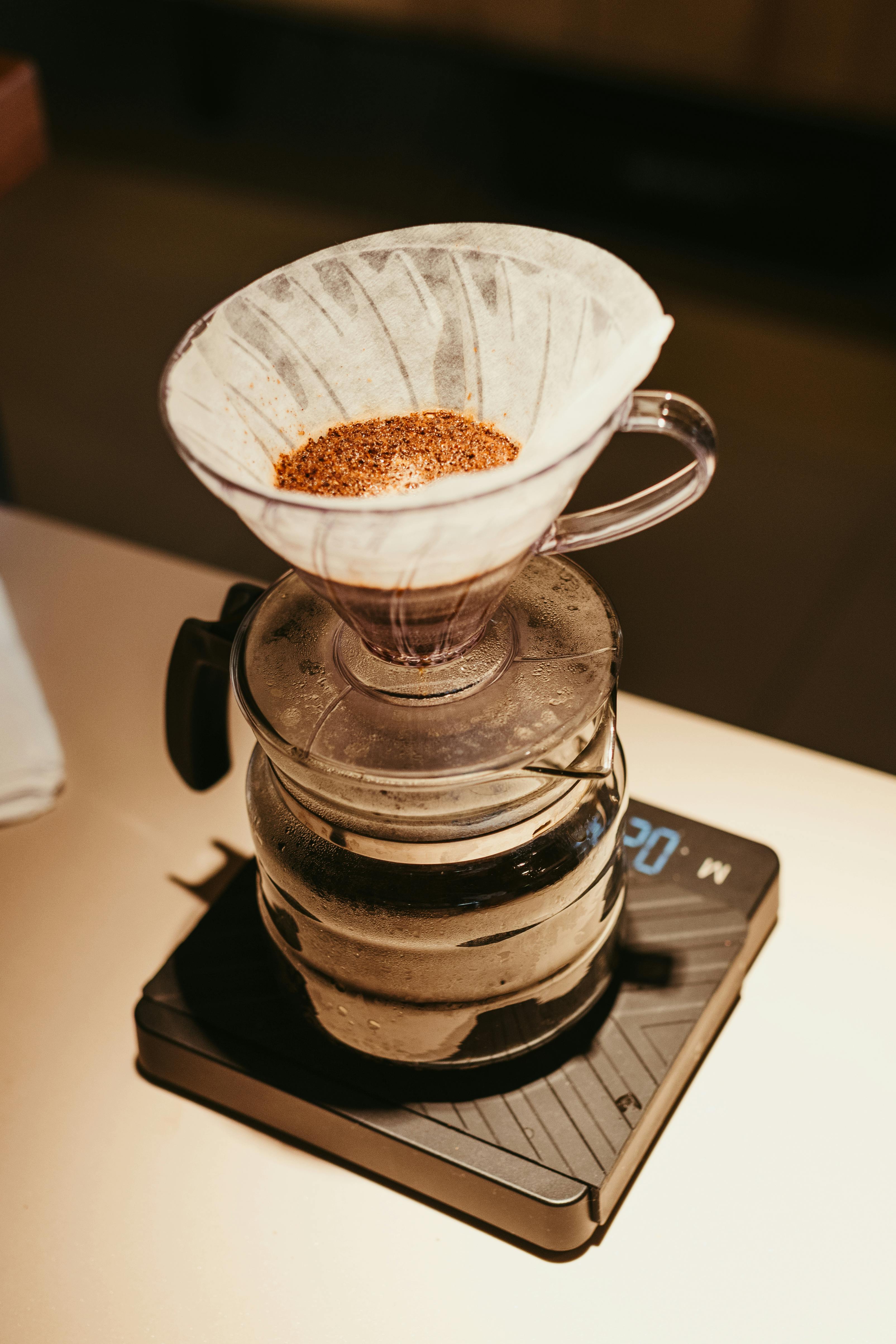 A coffee dripper on a scale with a cup of coffee · Free Stock Photo