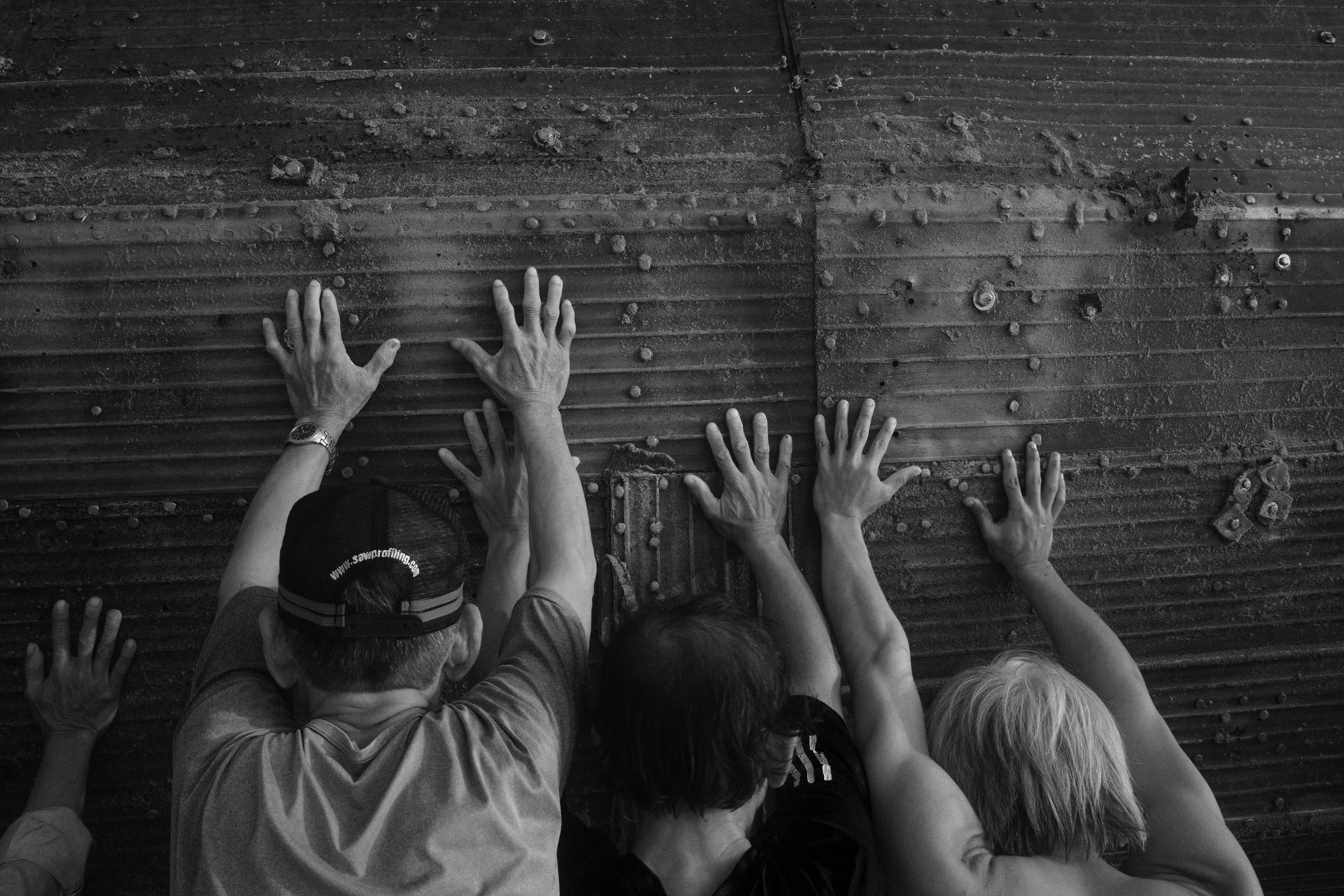 Back View of People Pushing on a Wall · Free Stock Photo
