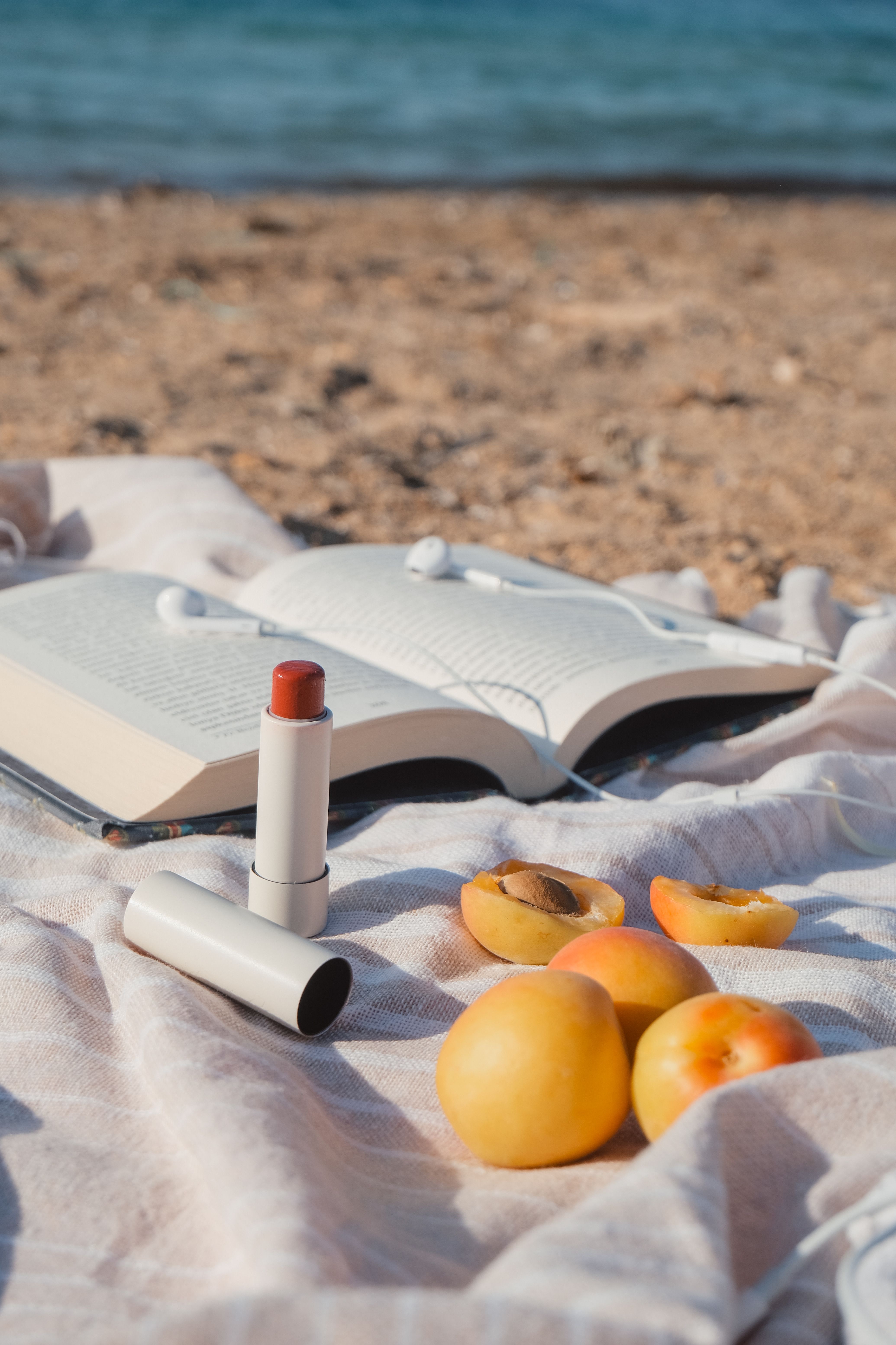 Selective Focus of Lipstick, Apricots, Book and Headphones on Blanket ...