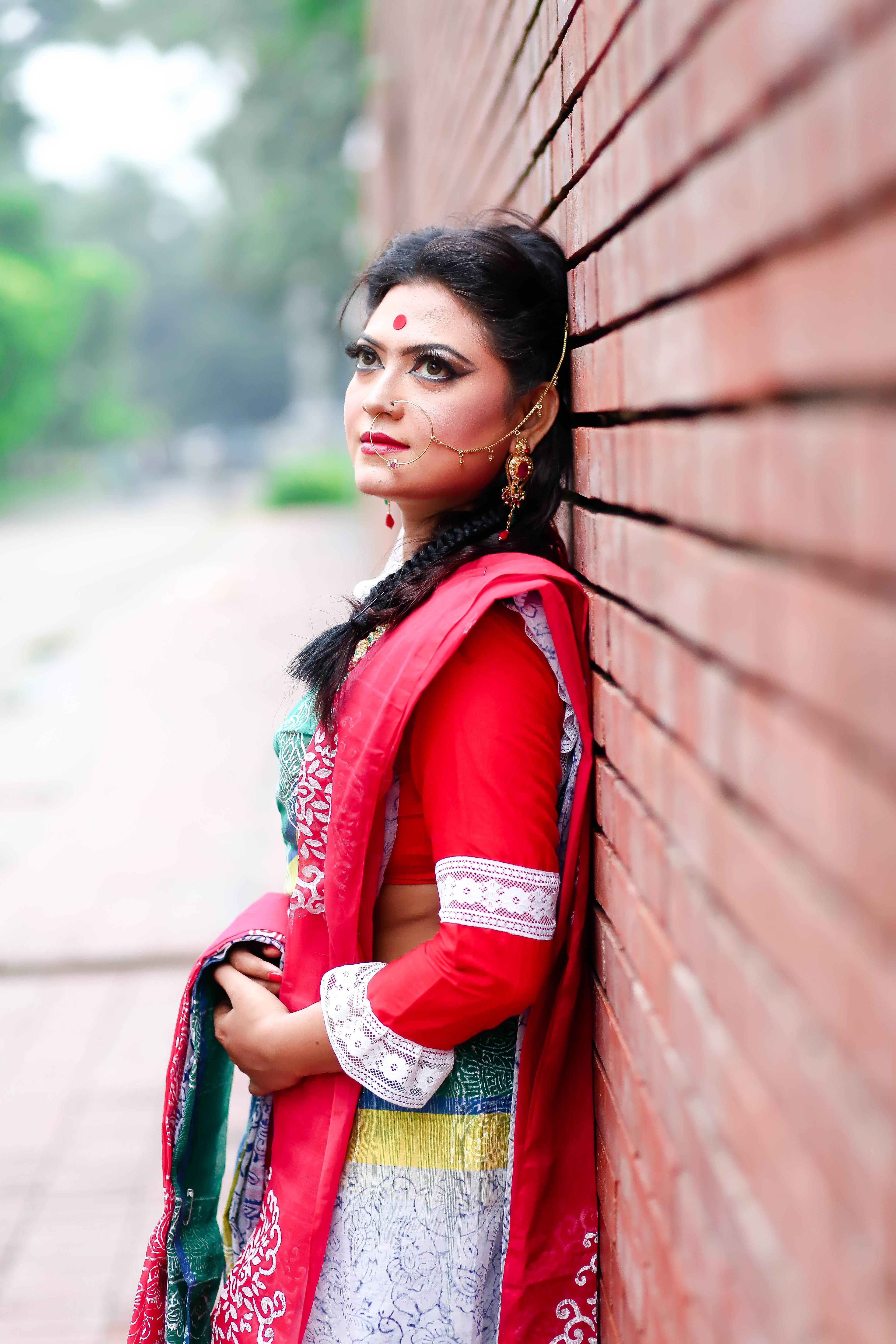 Female Model Wearing a Red Sari Leaning on a Brick Wall · Free Stock Photo