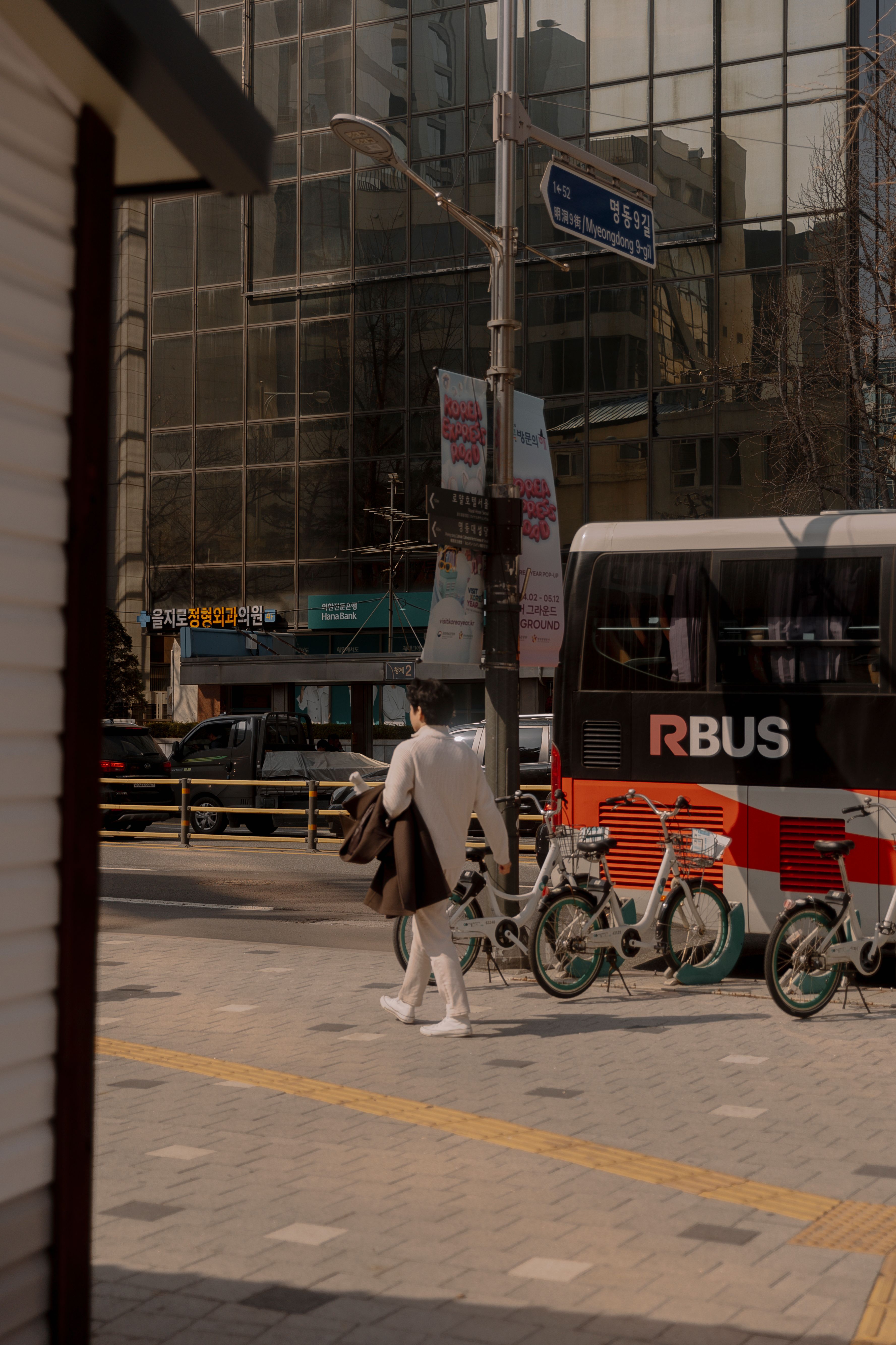 A person walking down a sidewalk next to a bus · Free Stock Photo