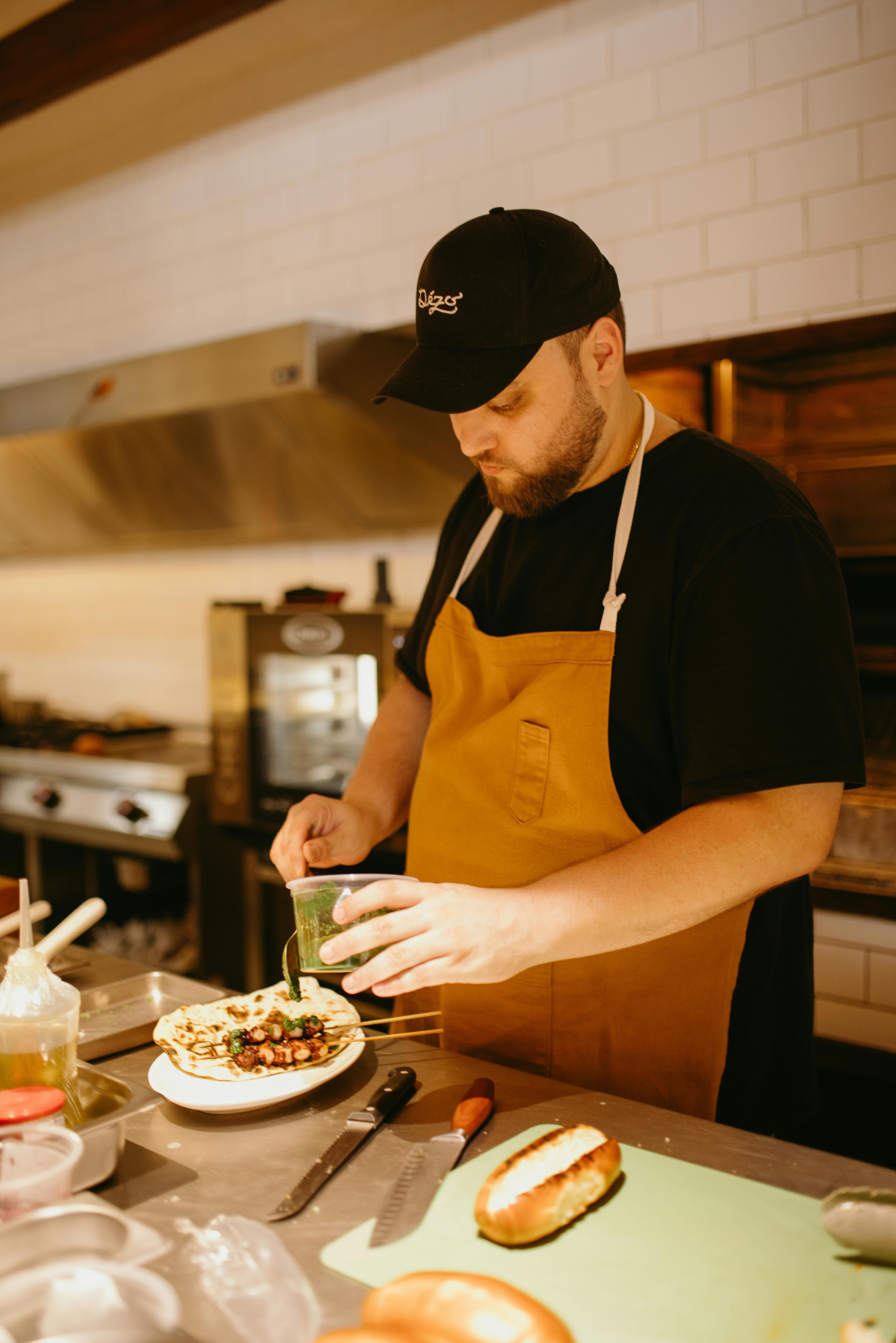 Man in a Cap and Yellow Apron Preparing Food · Free Stock Photo