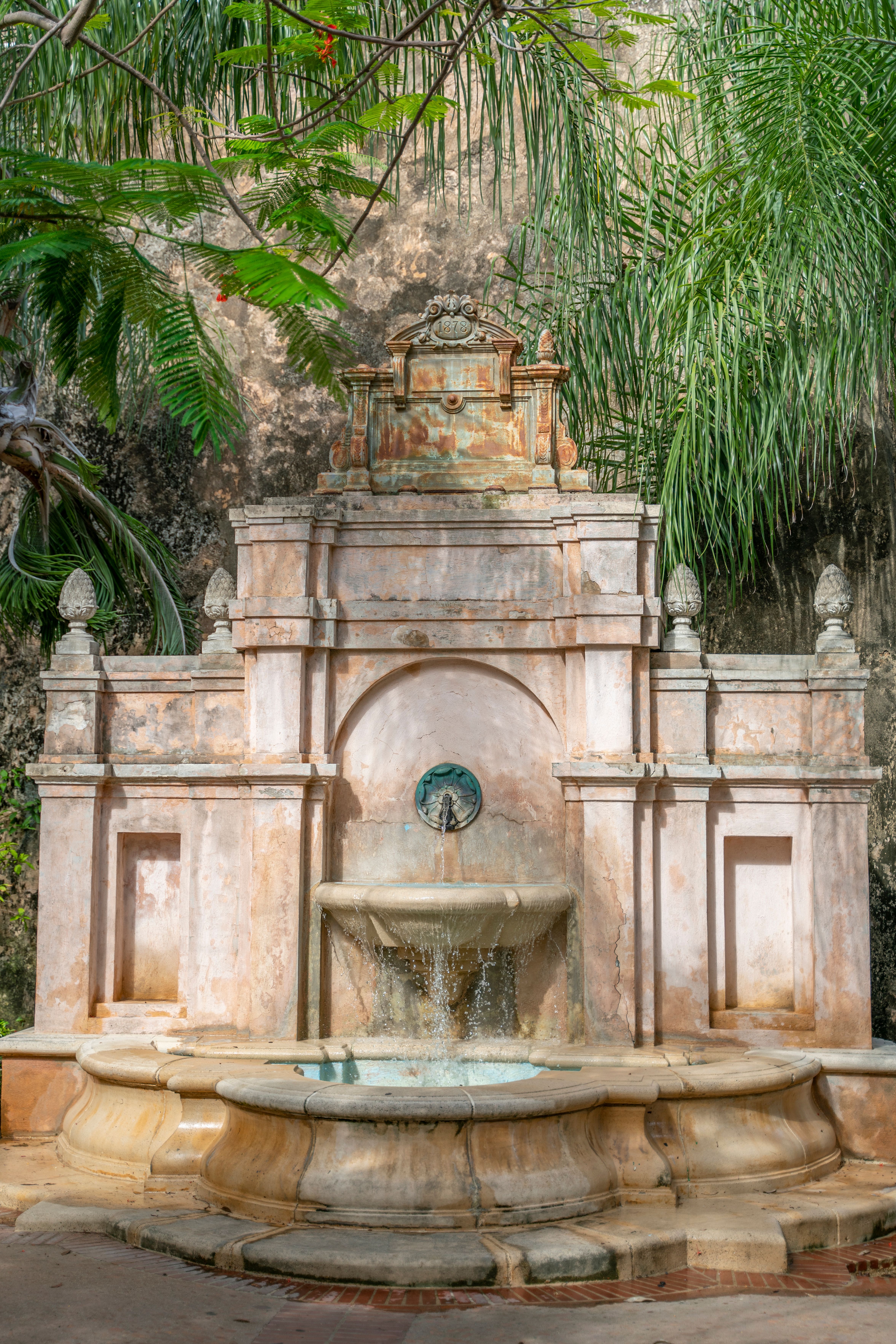 A fountain in a tropical setting with palm trees · Free Stock Photo