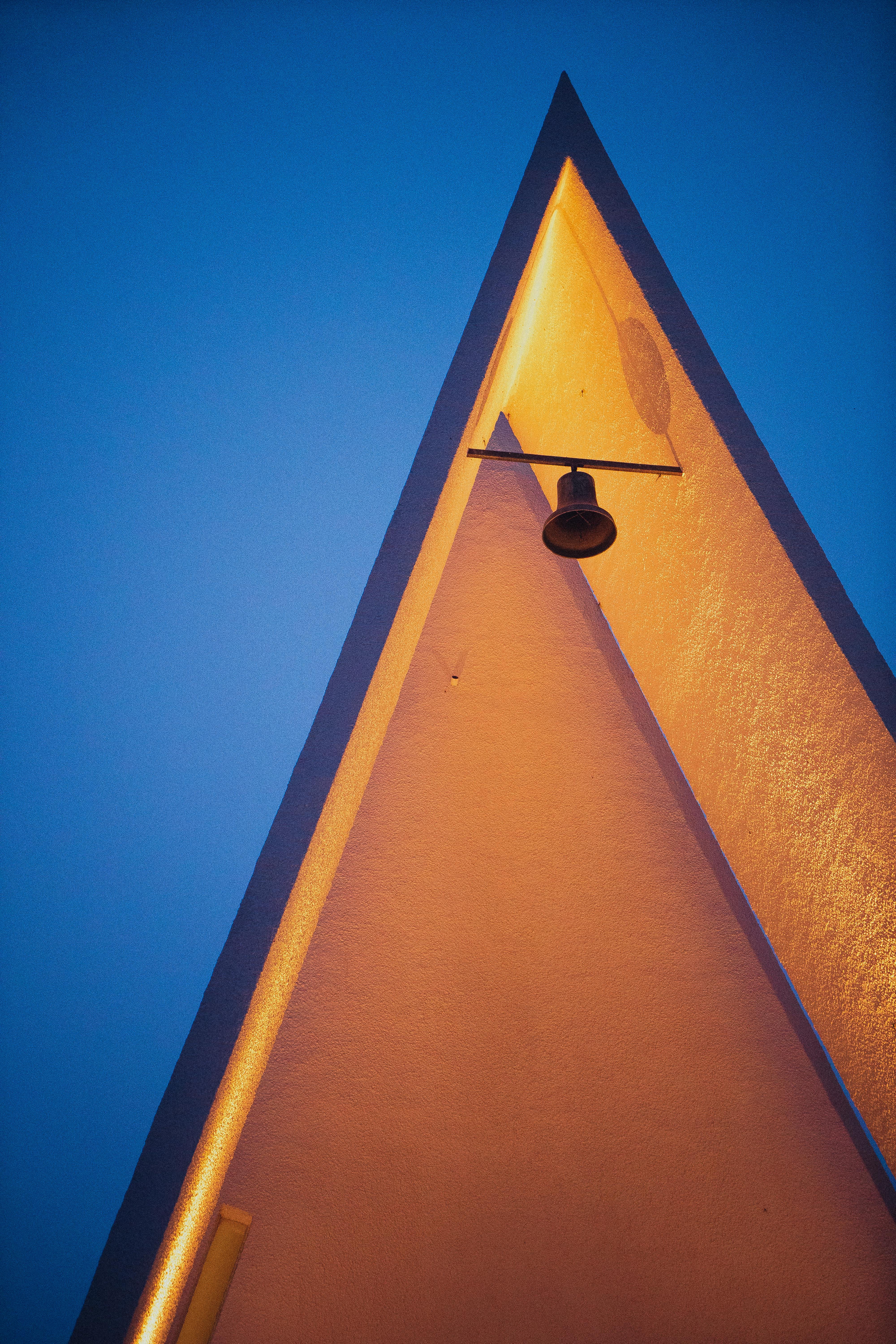 A triangle shaped building with a bell on top · Free Stock Photo