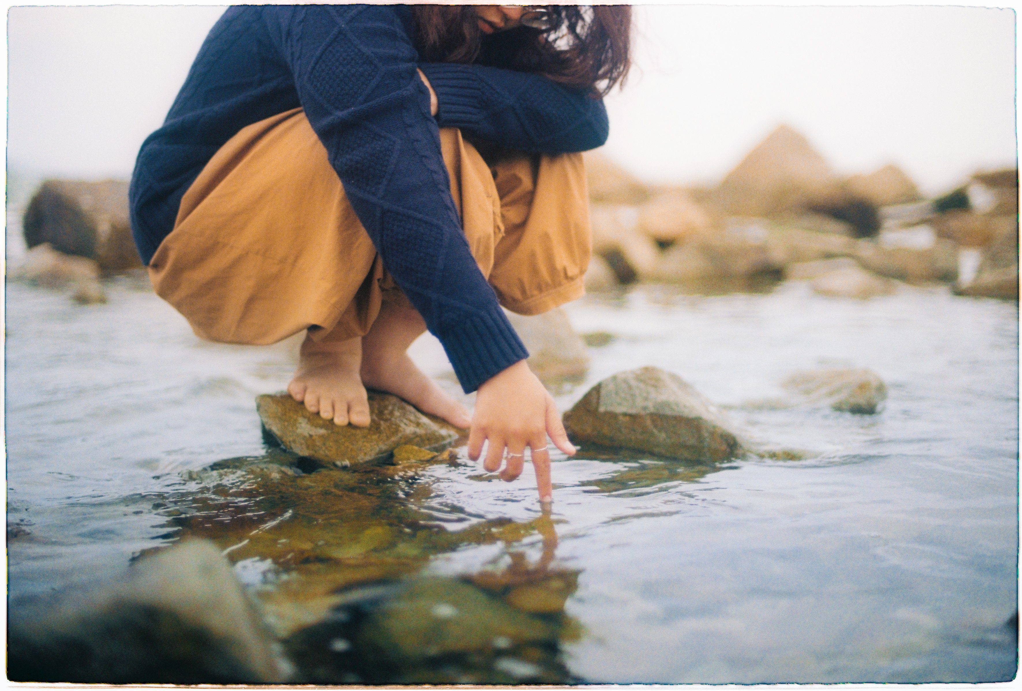Woman Squatting on Stones over Water · Free Stock Photo