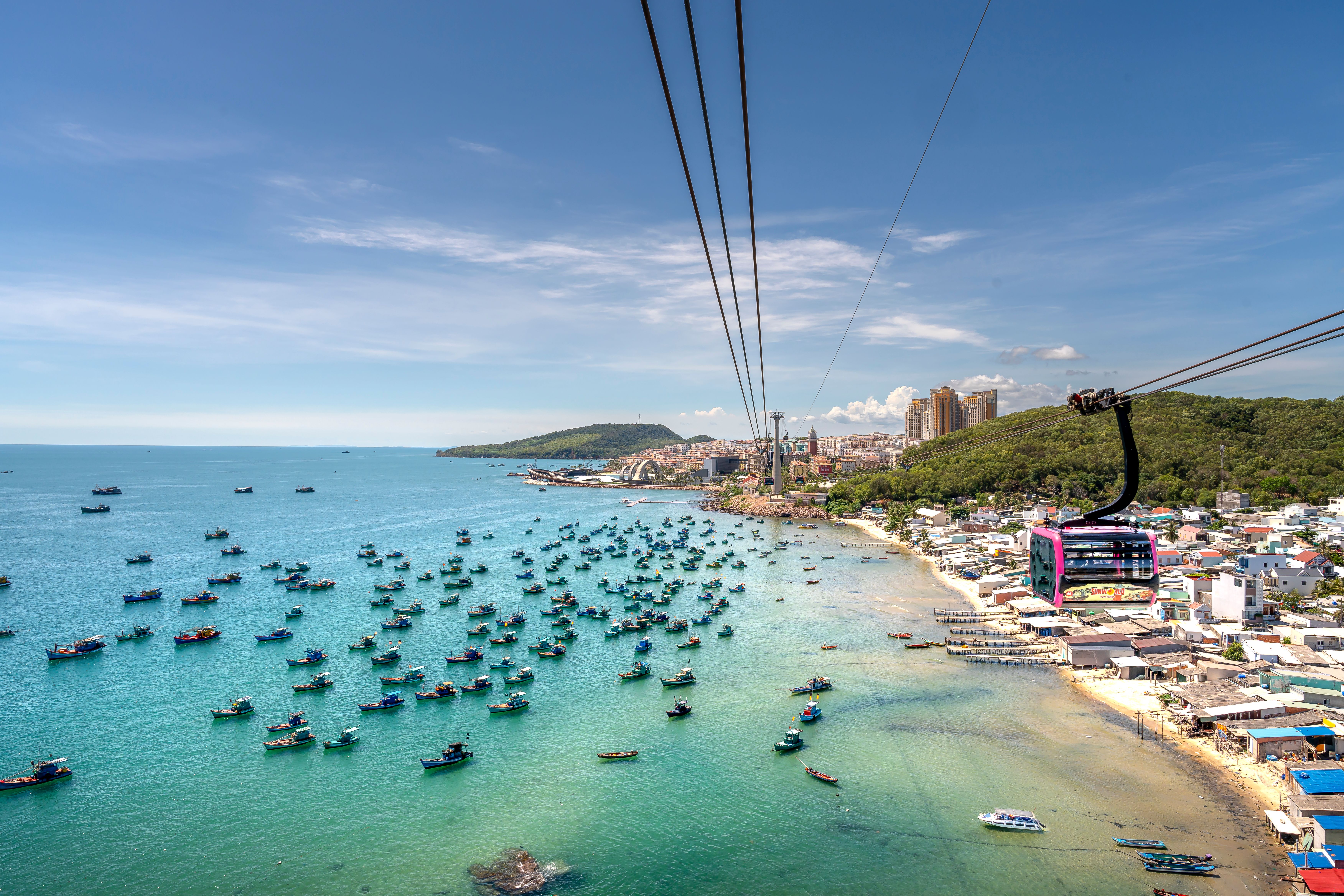 A cable car that goes over the ocean with boats · Free Stock Photo