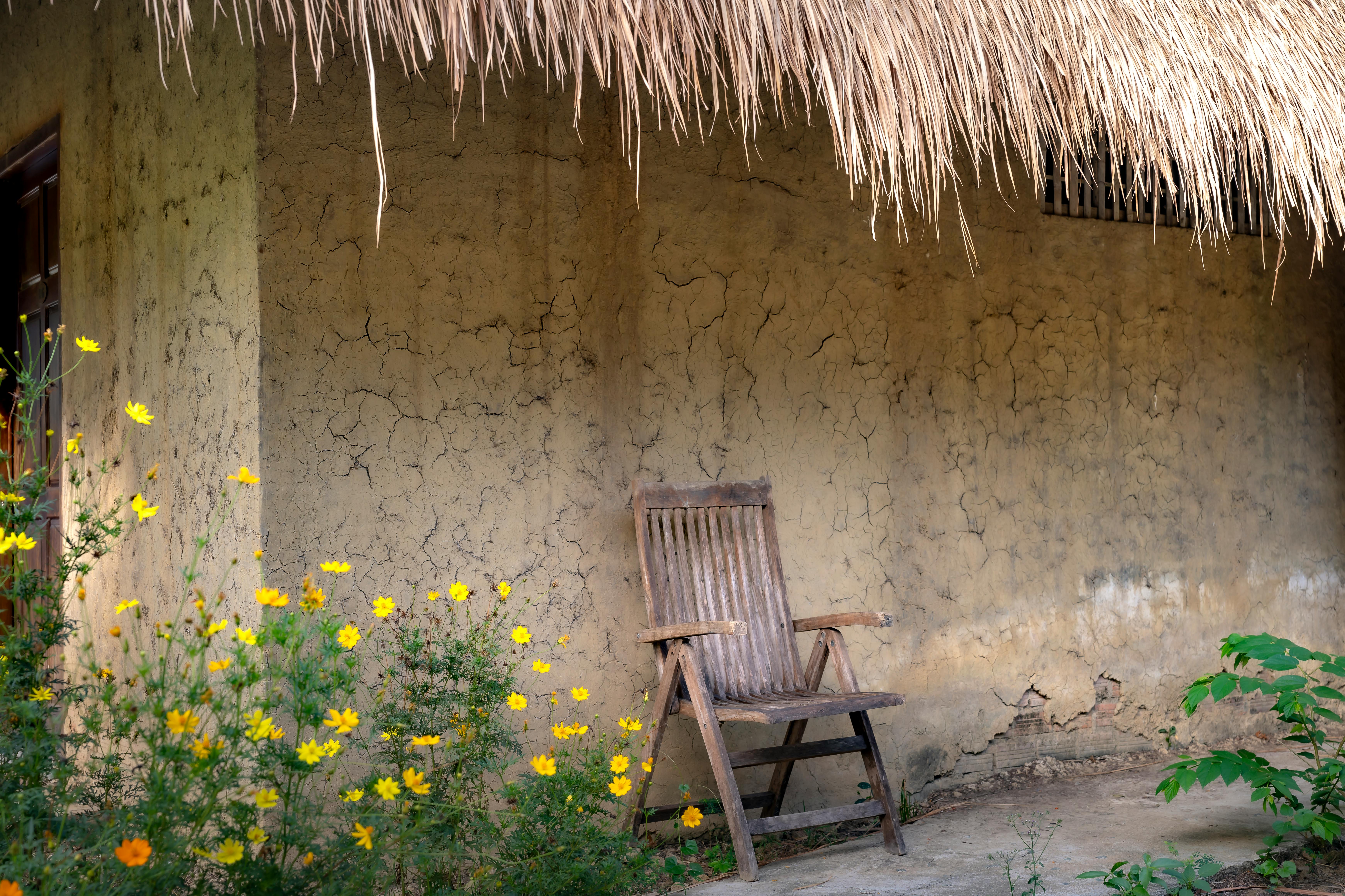 A chair sitting in front of a thatched roof · Free Stock Photo