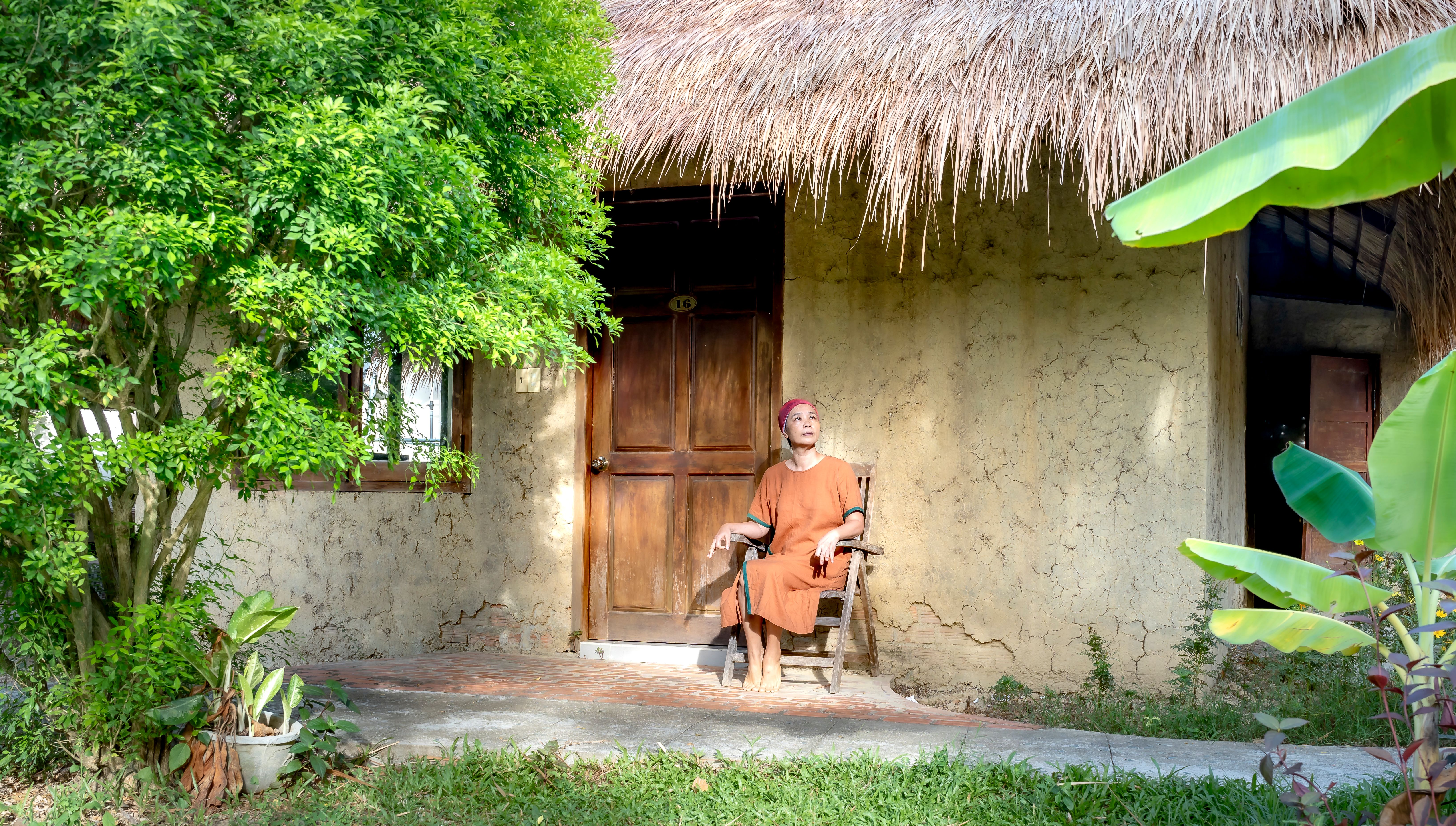 A man sitting in front of a thatched hut · Free Stock Photo