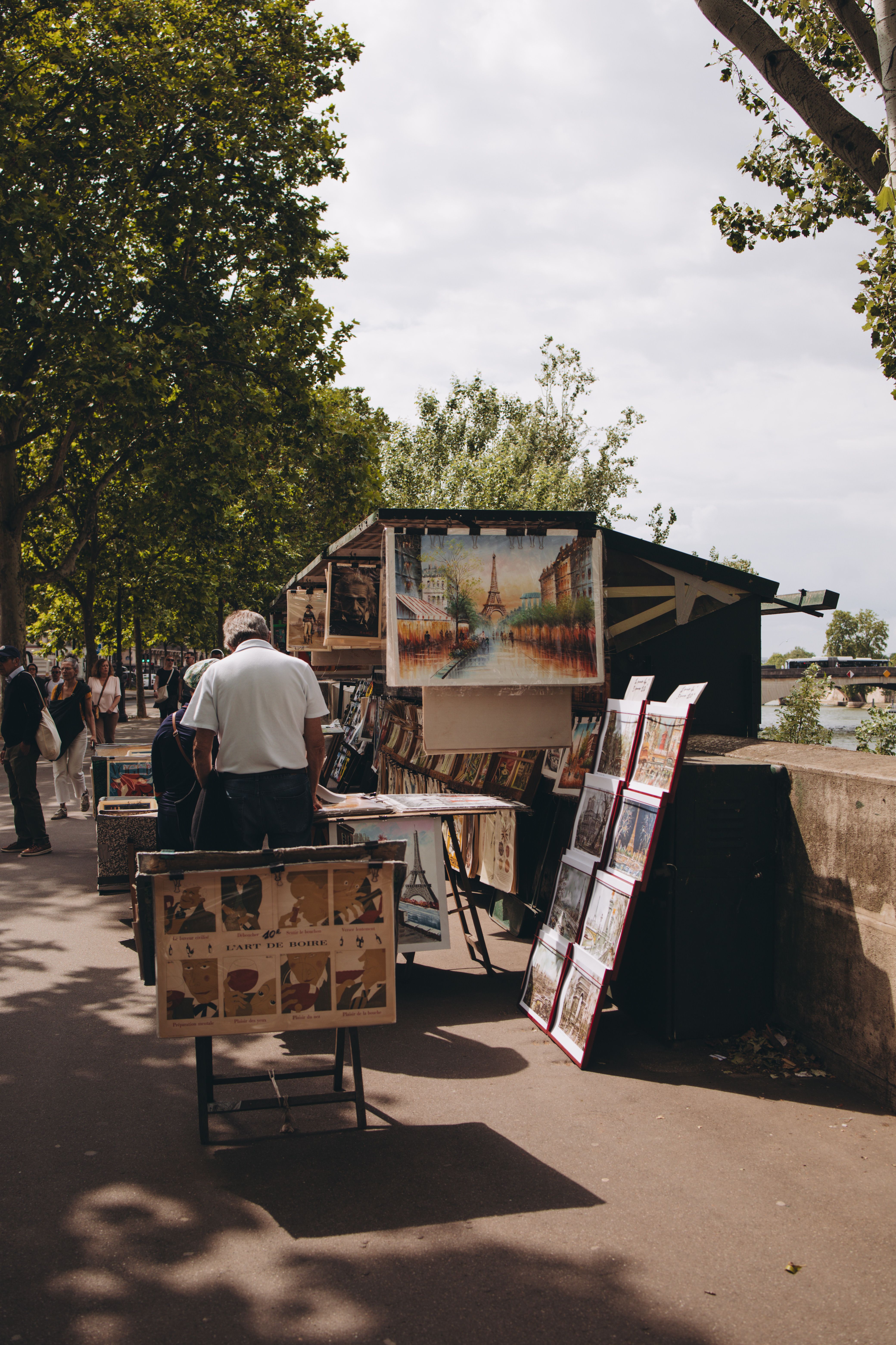 Man Standing next to Stall Selling Paintings on Street · Free Stock Photo