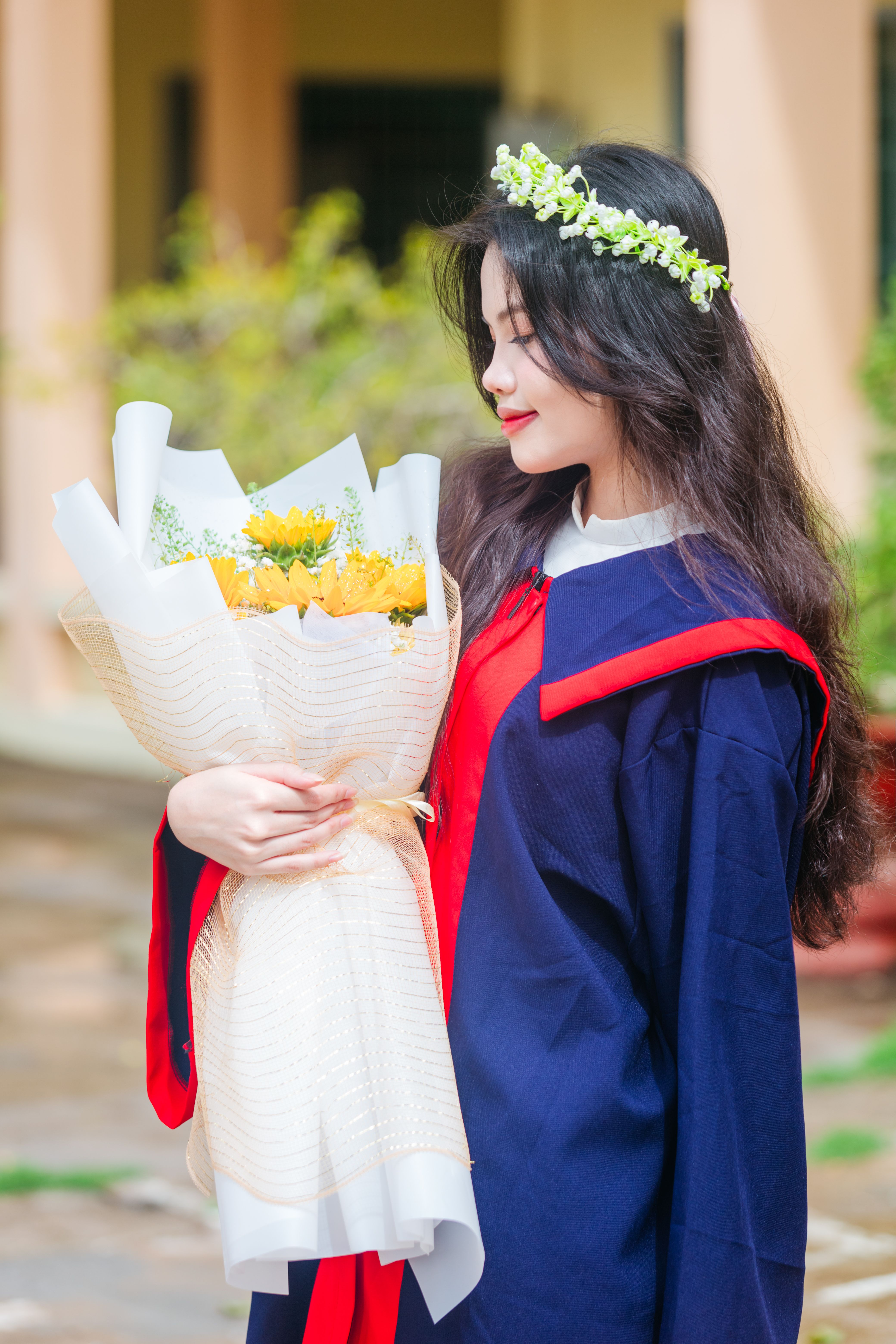 A Young Woman in a Graduation Gown Holding a Bouquet · Free Stock Photo