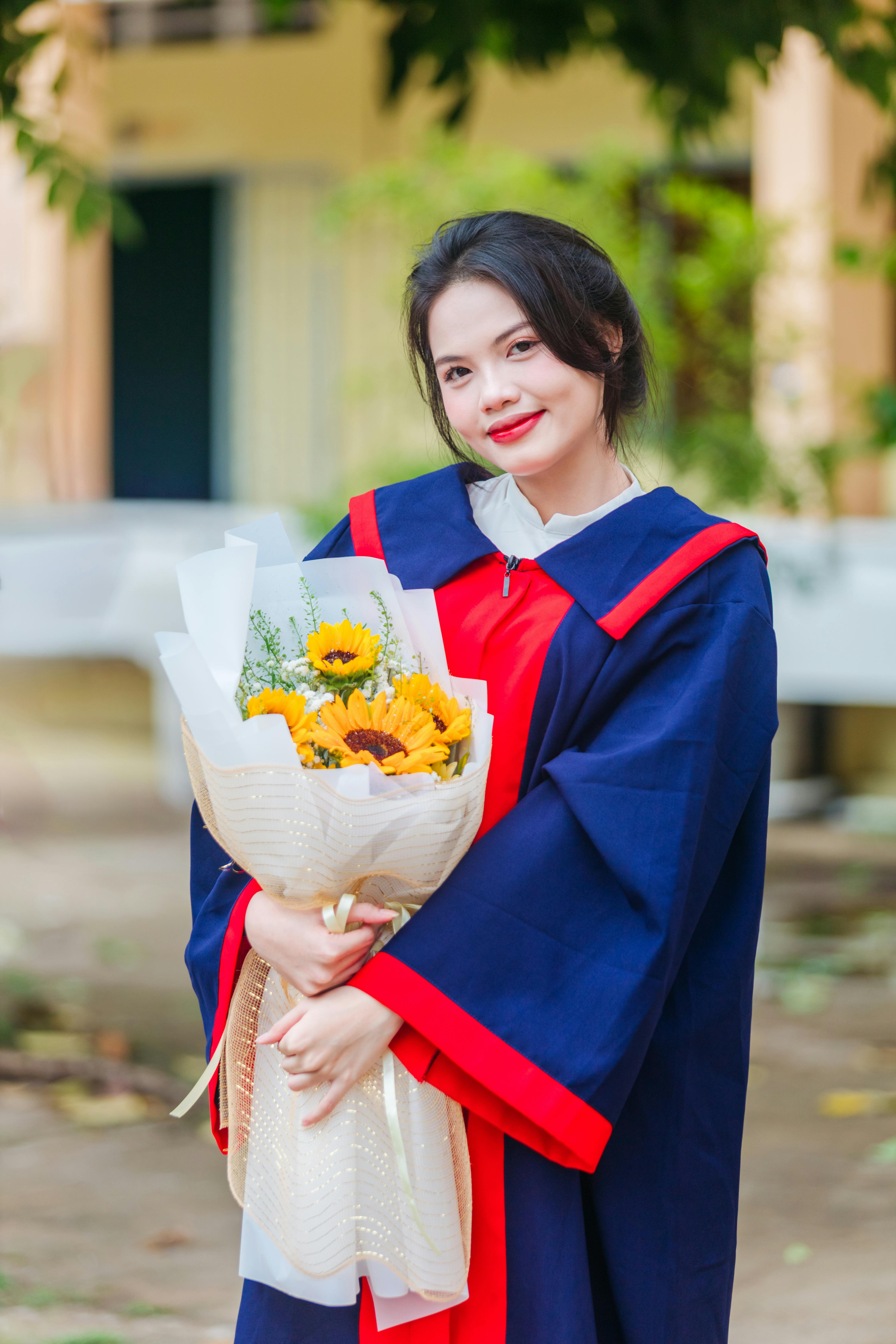 Smiling Woman Wearing Graduation Toga Holding a Sunflowers Bouquet ...
