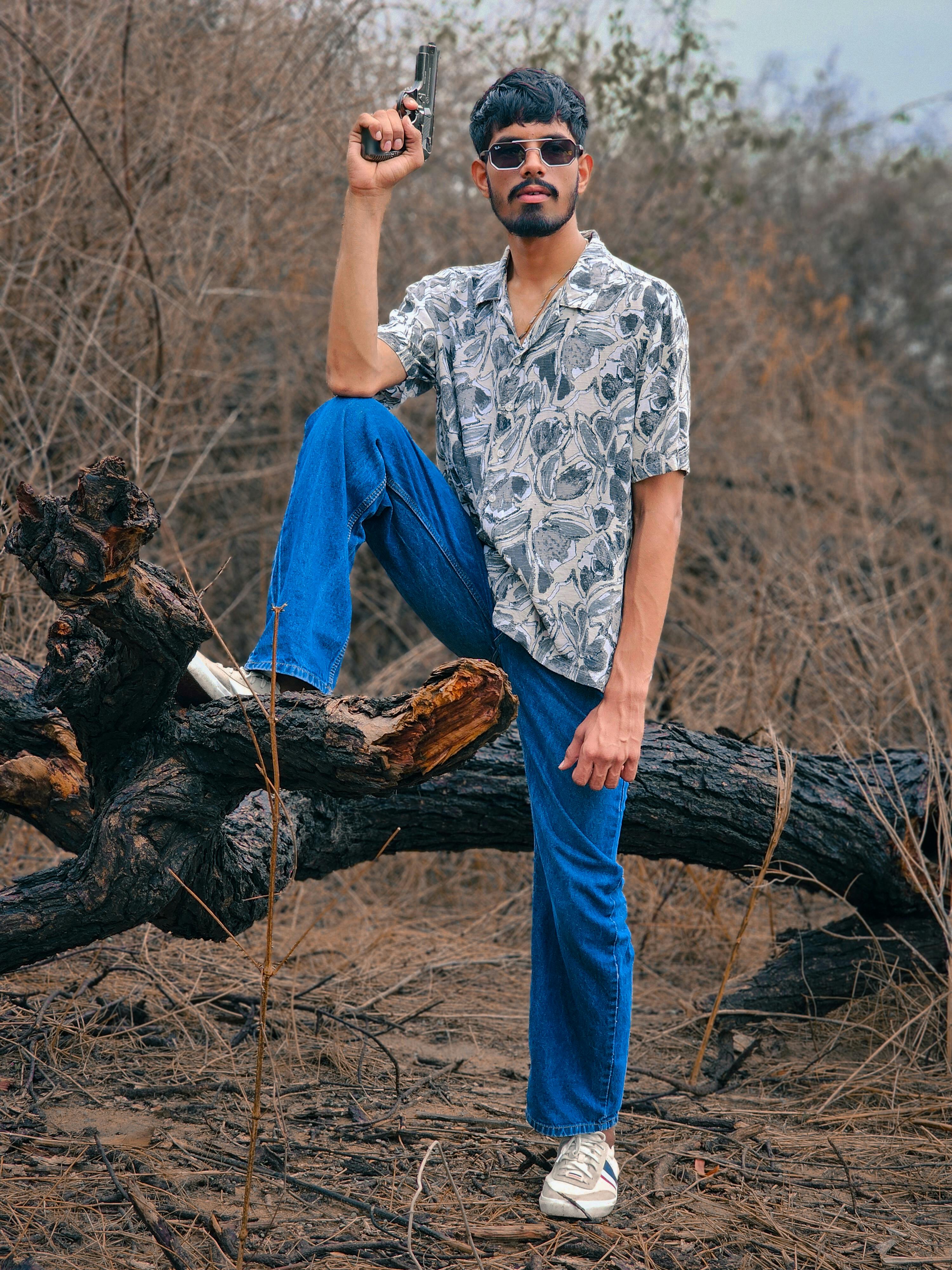 Male Model Posing on a Dead Fallen Tree with a Gun in Hand · Free Stock ...