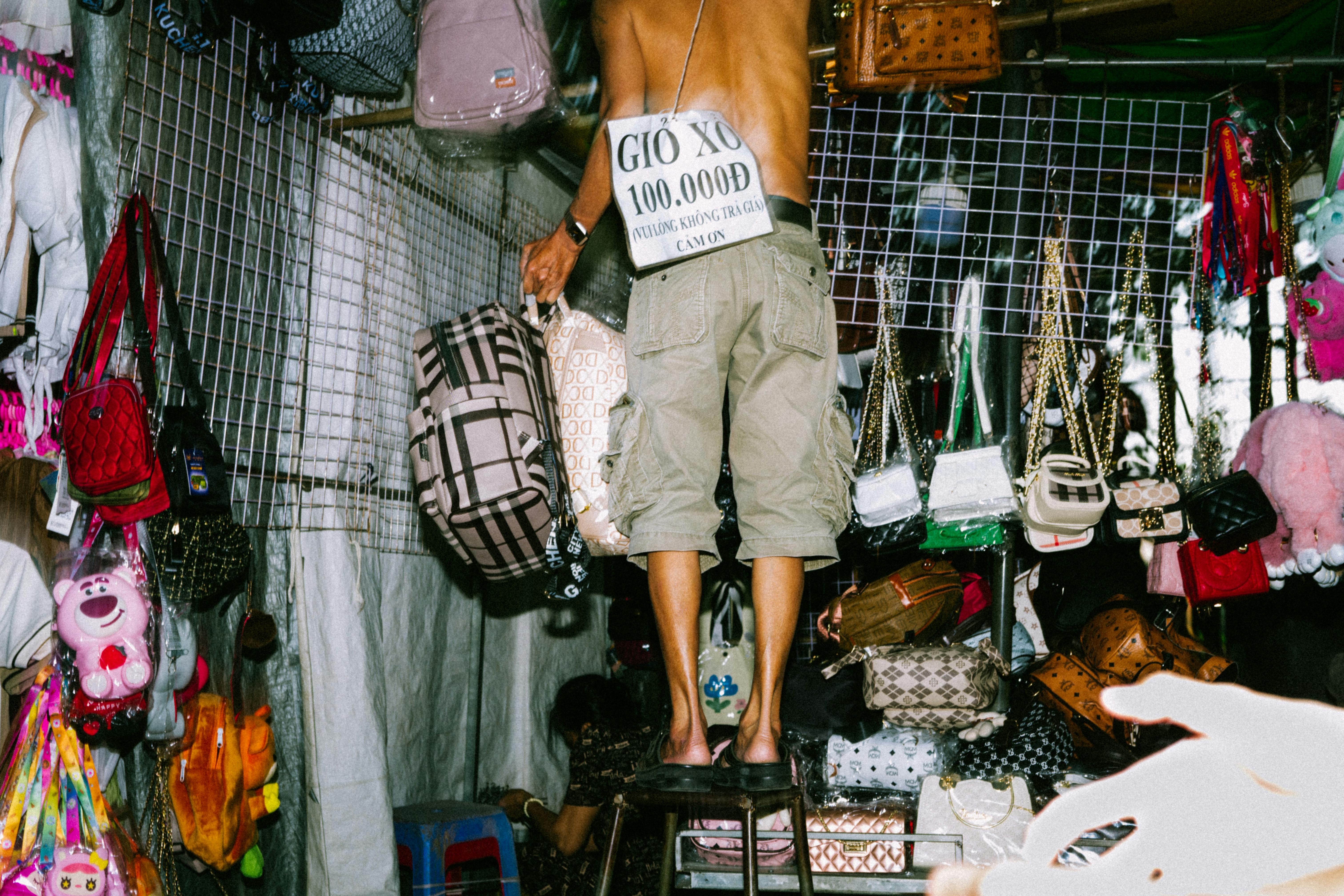 Man Selling Handbags at an Outdoor Market Stall · Free Stock Photo