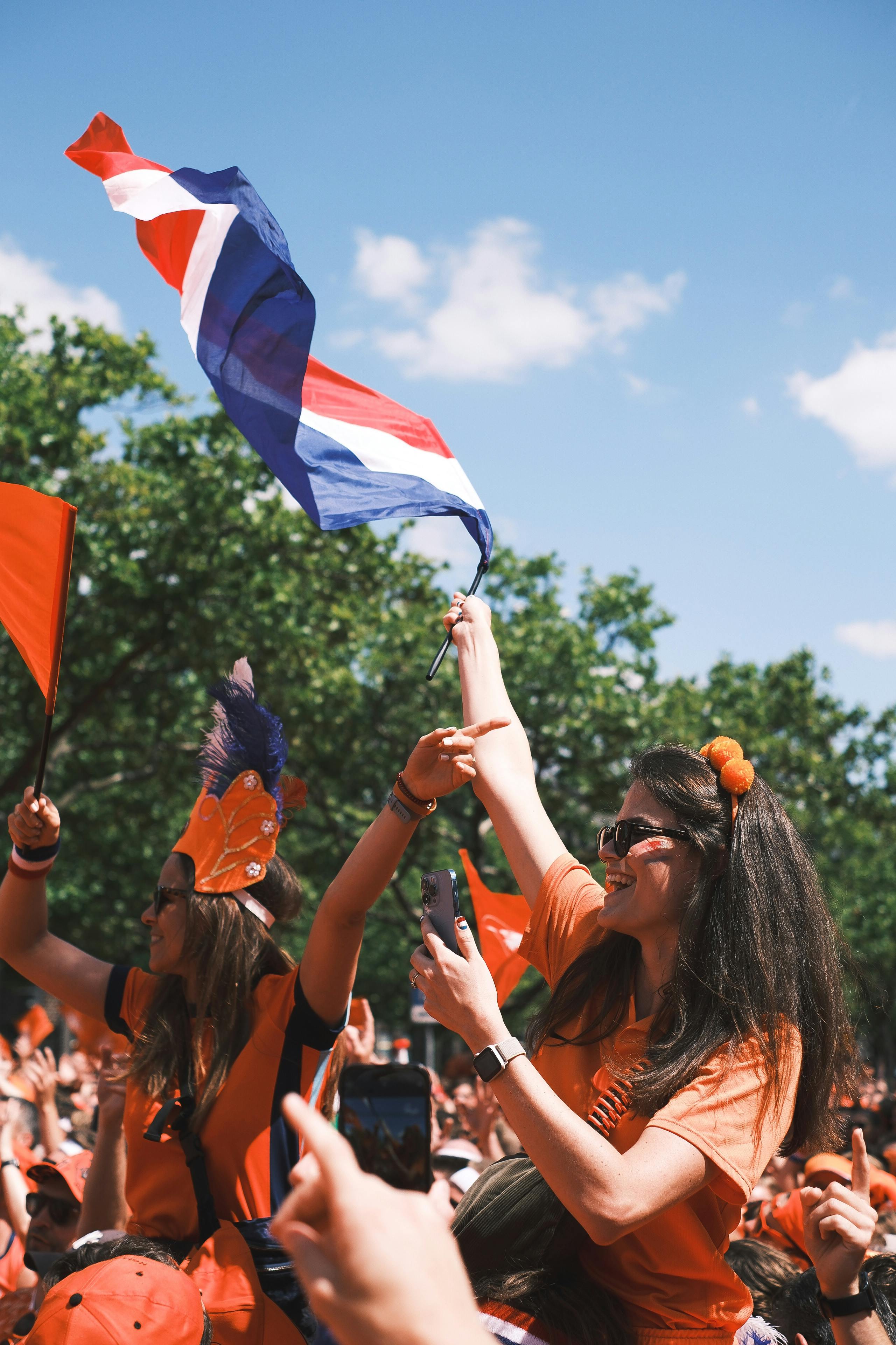 A Crowd in Orange T-shirts Cheering and Waving the Flags · Free Stock Photo
