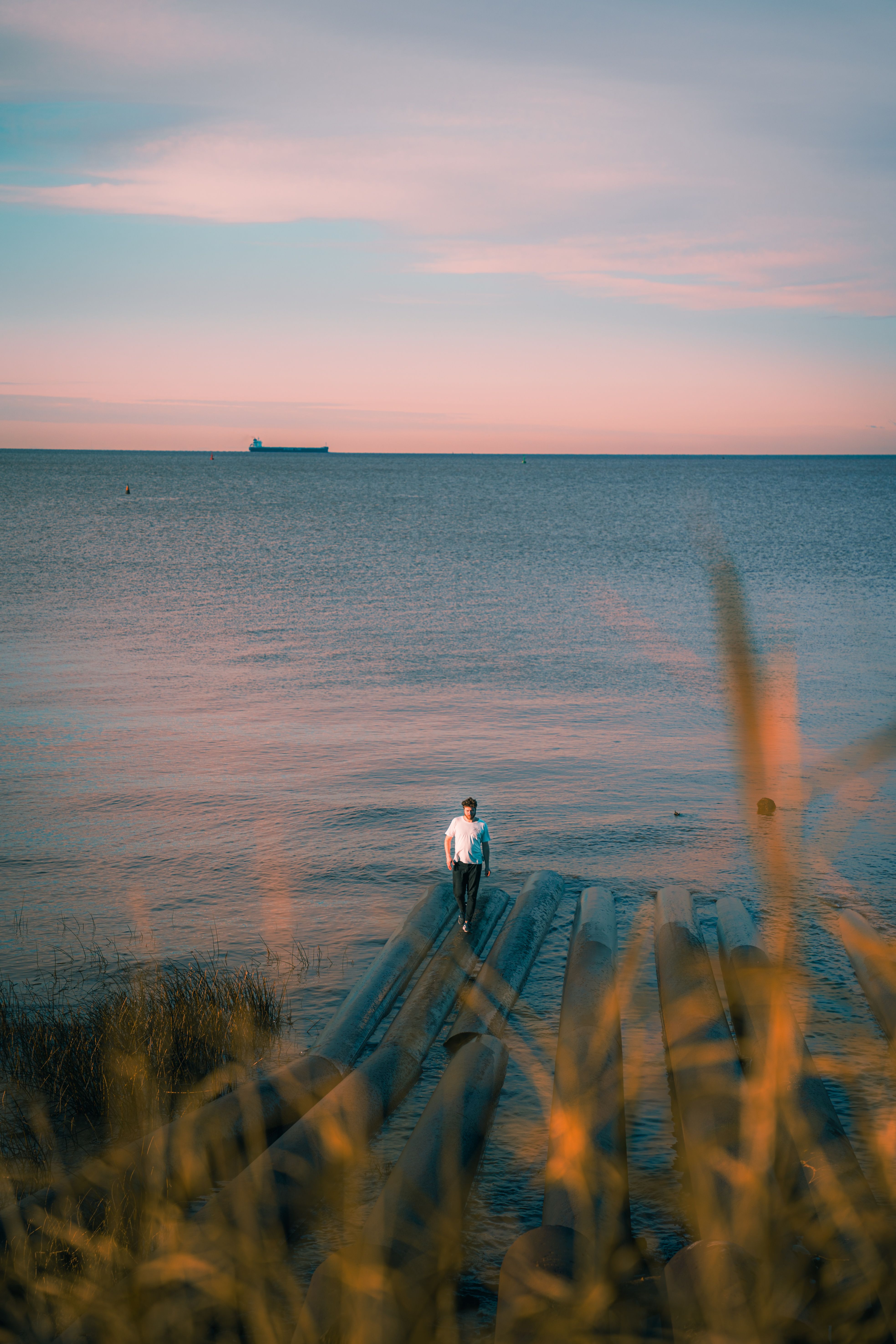 Man Walking on Pipes on Sea Shore at Dusk · Free Stock Photo