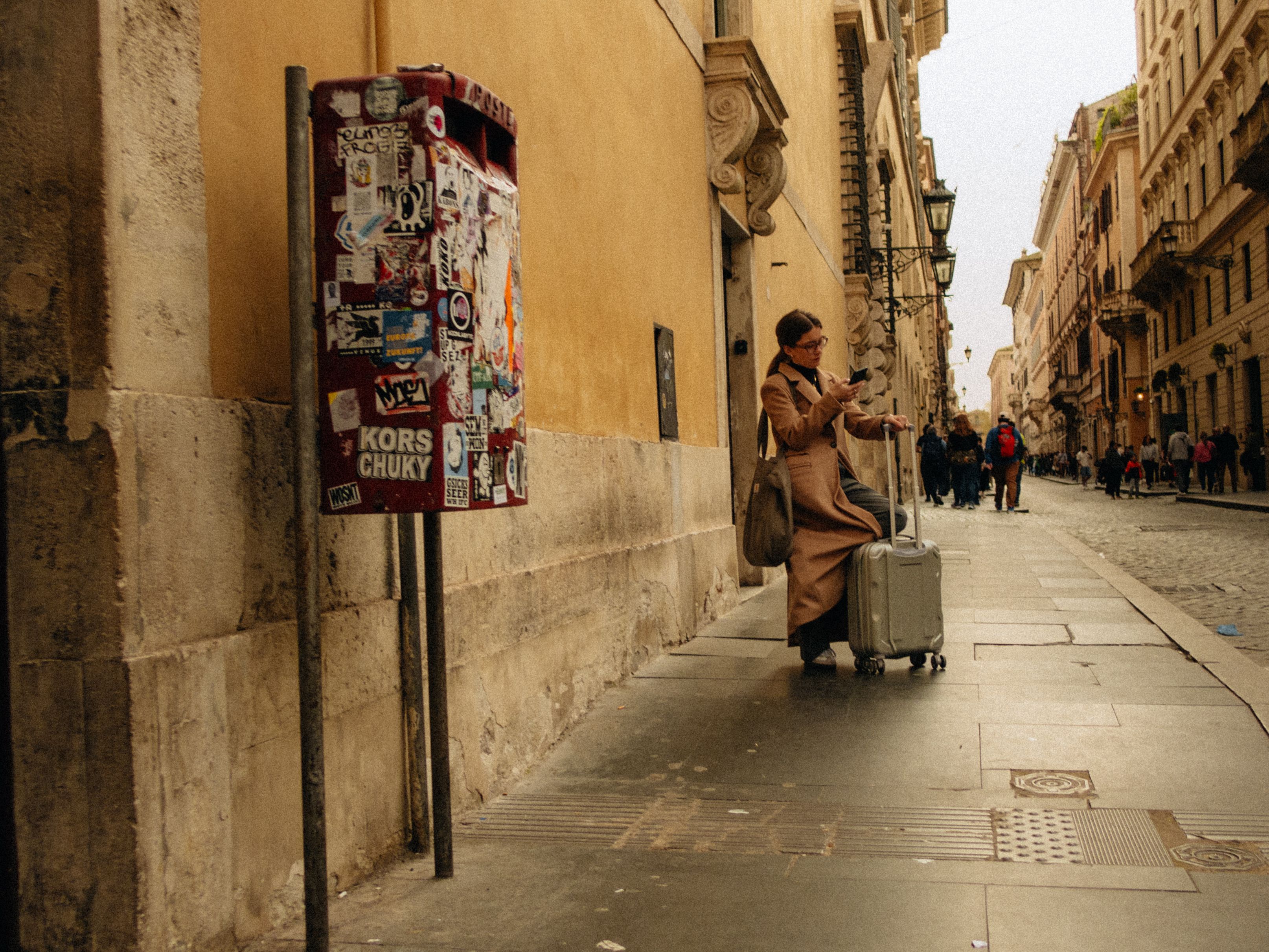 A woman with a suitcase walks down a street · Free Stock Photo