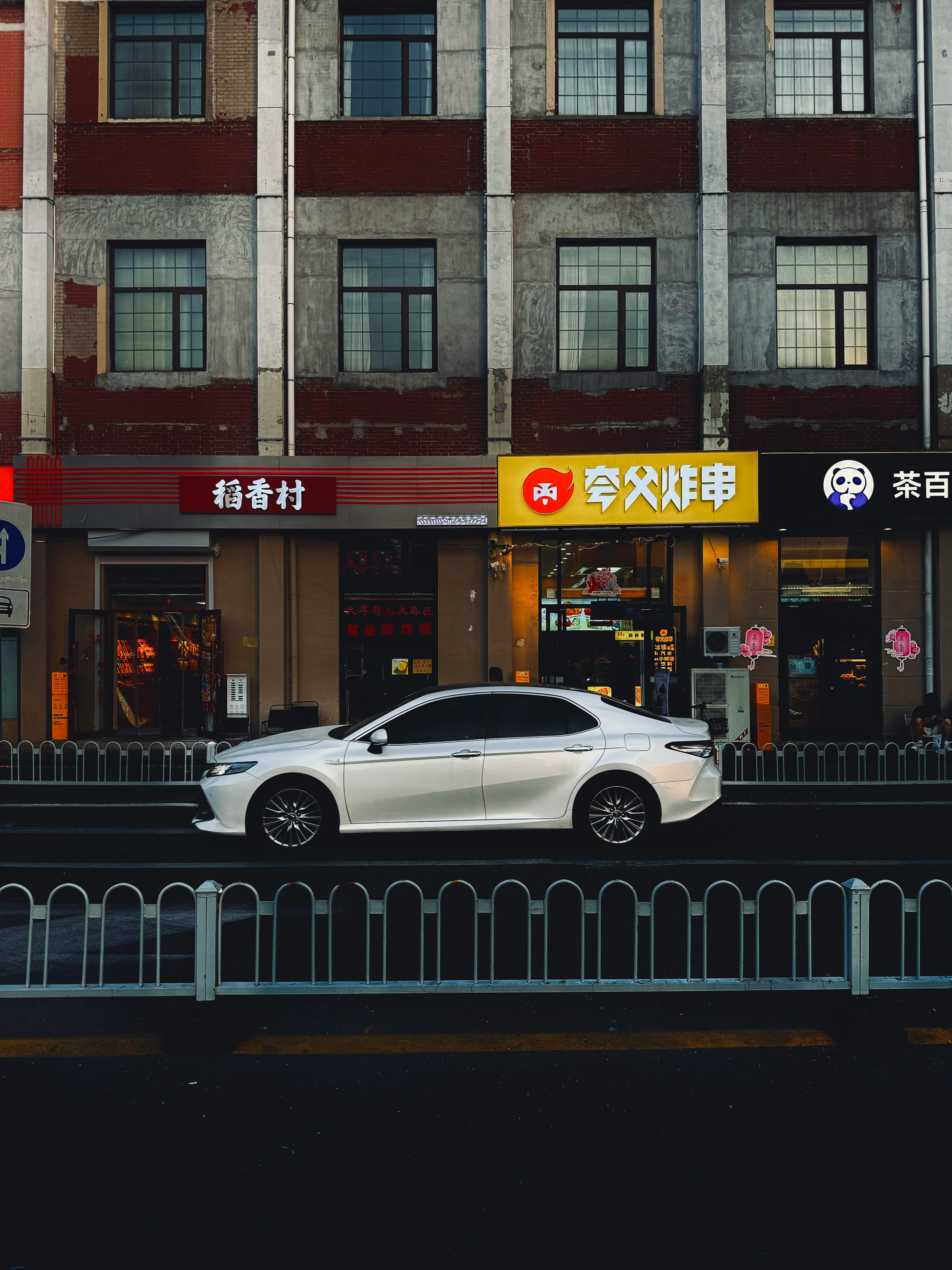A White Toyota Camry Driving on the Street in a City · Free Stock Photo