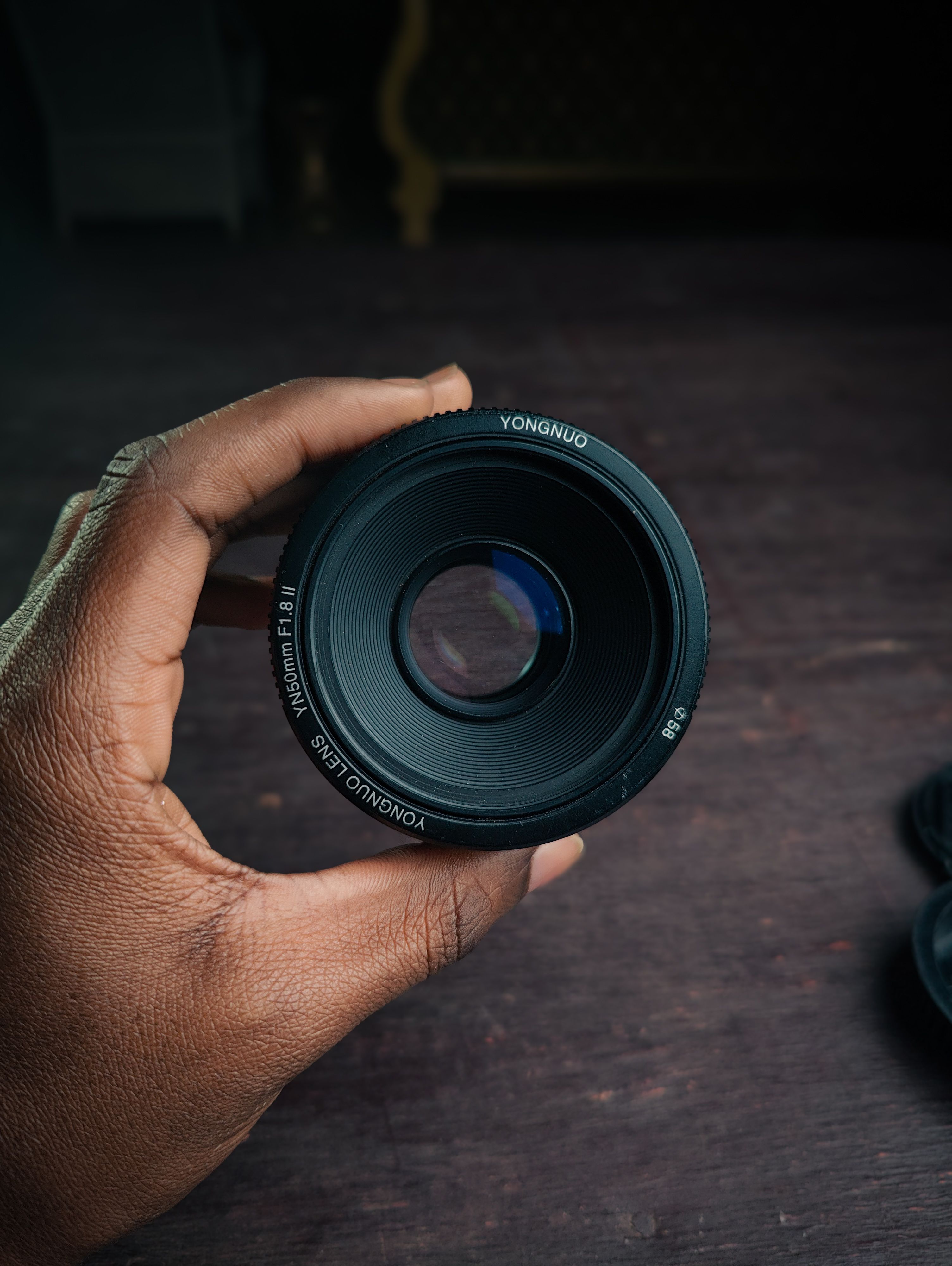 Camera lens and lens cap in moody lighting on table. 50mm Yongnuo lens ...