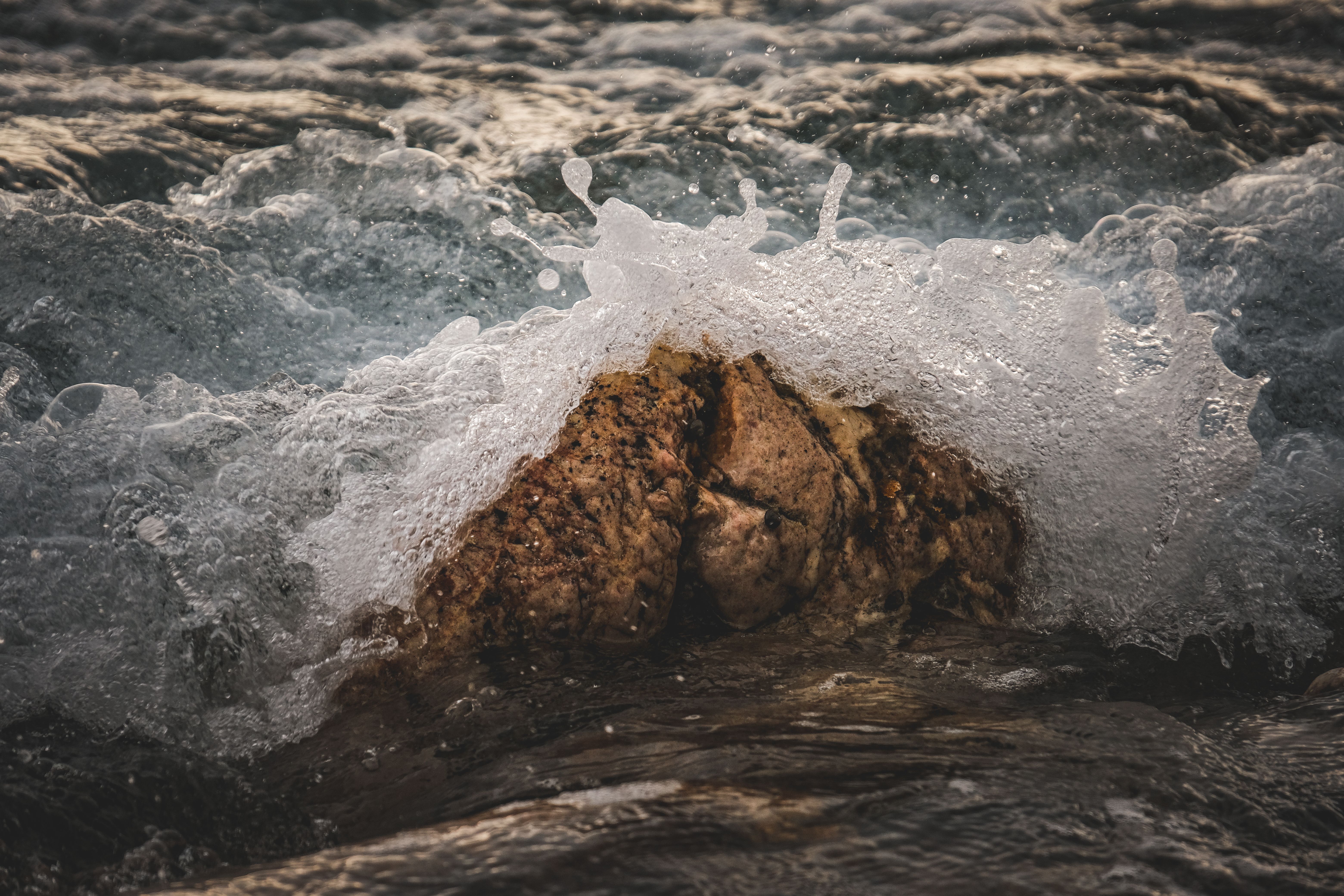 A wave crashing into a rock in the ocean · Free Stock Photo