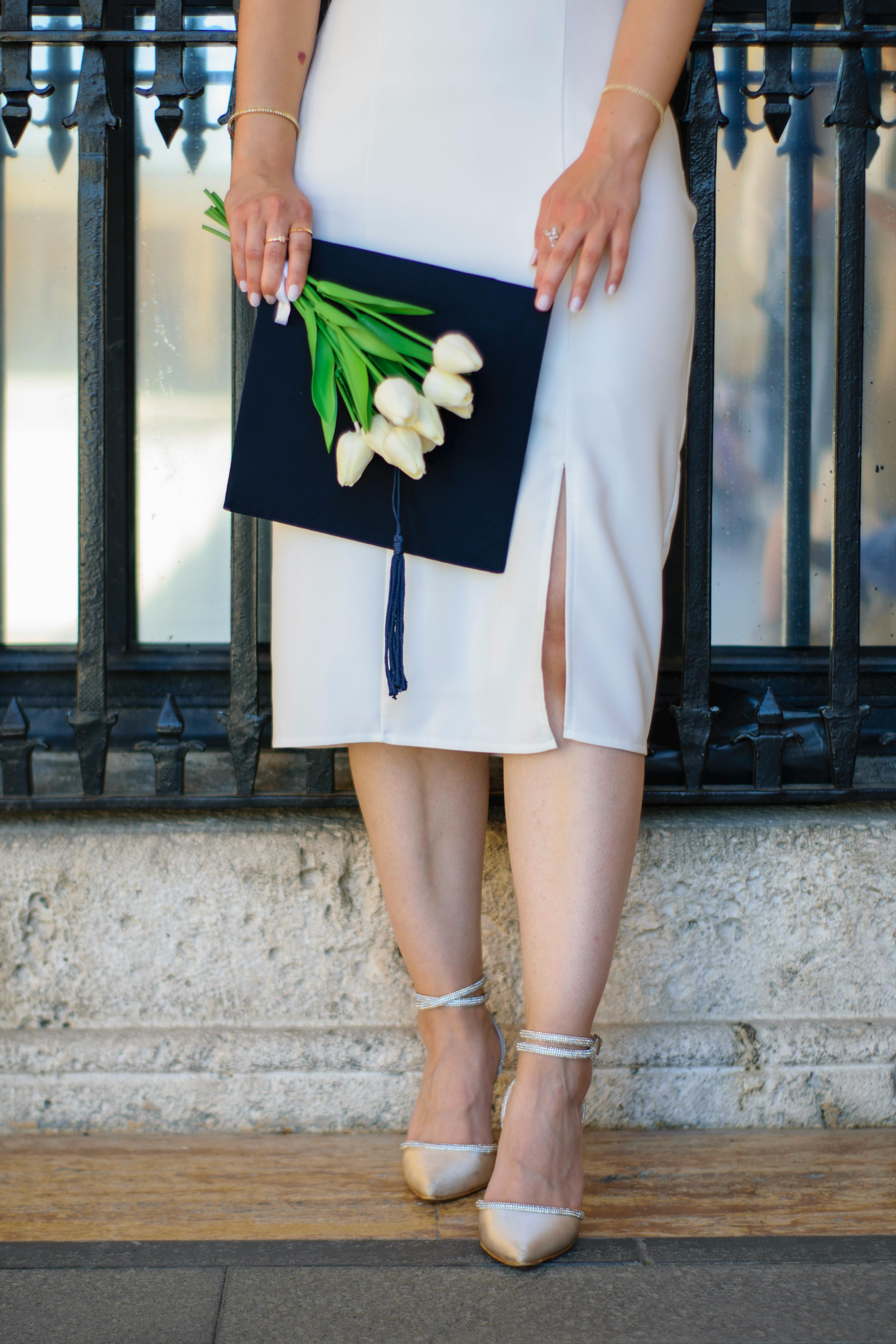 Woman in a White Dress With a Bouquet of White Tulips and a Graduation ...