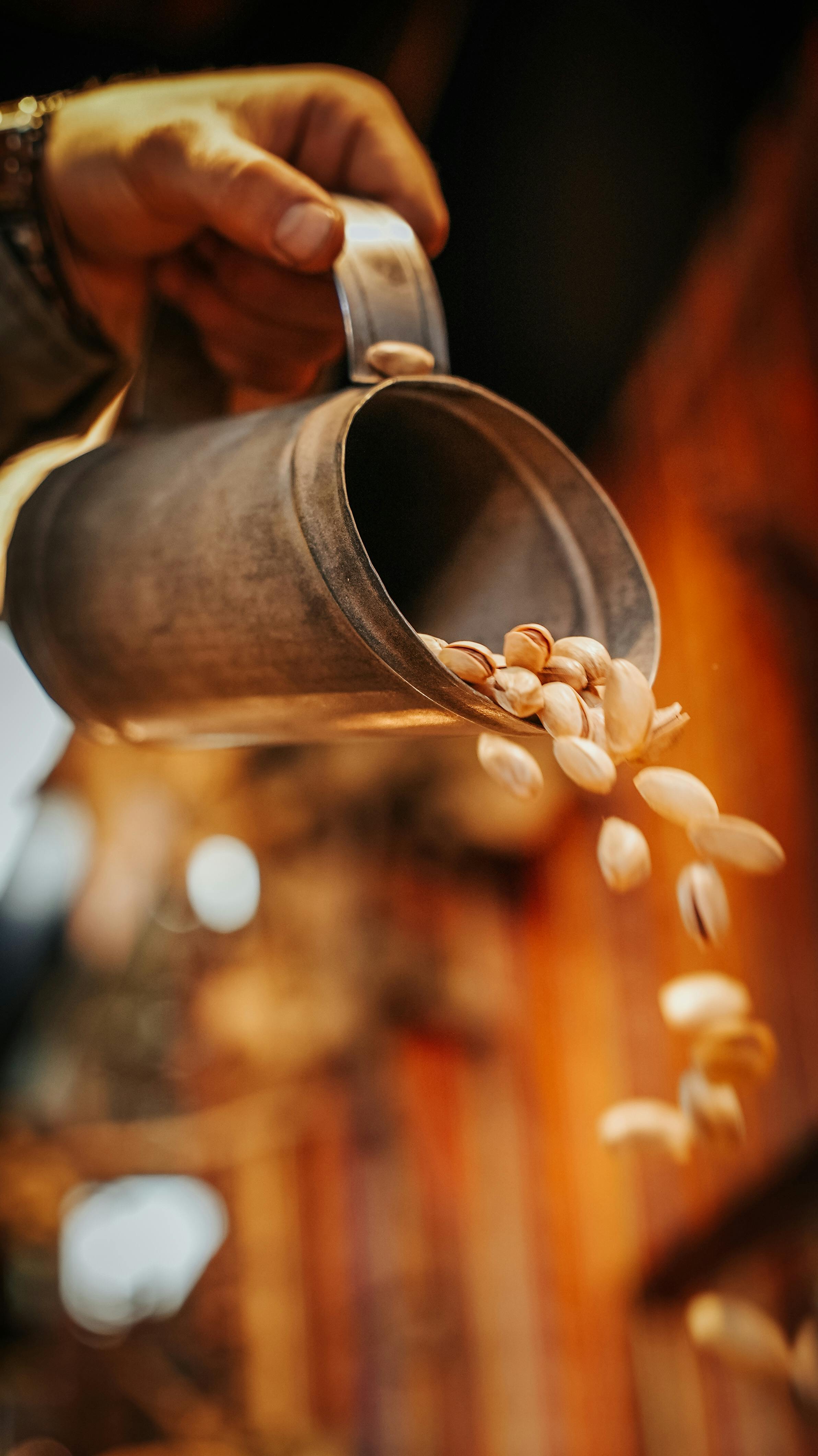 A person pouring nuts into a metal container · Free Stock Photo